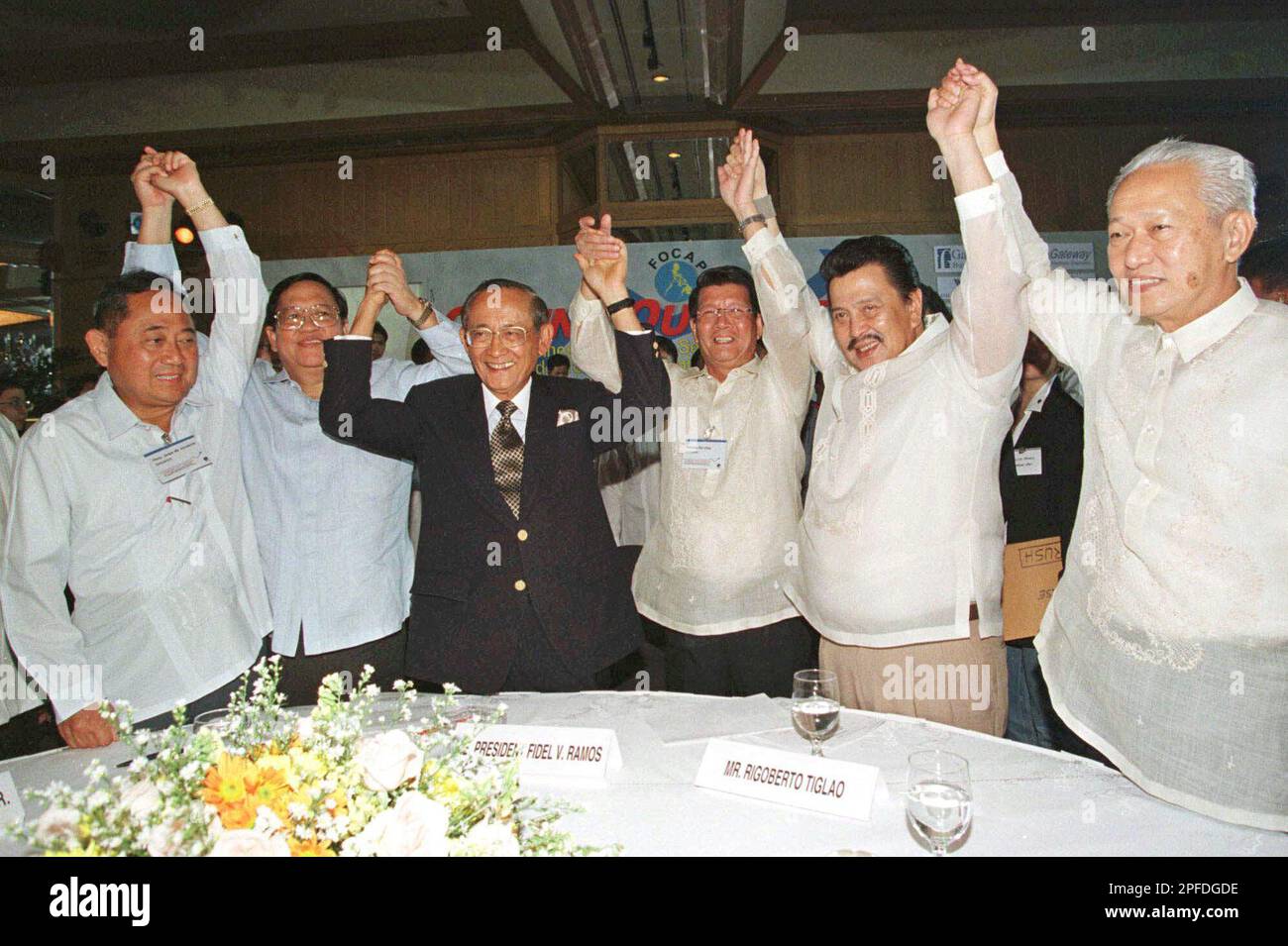 Philippine President Fidel Ramos, in dark suit, raises the hands of ...