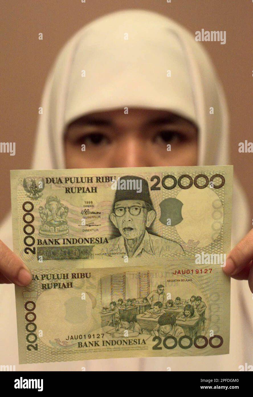 An Indonesian woman in traditional Muslim dress displays the new 20,000 ...
