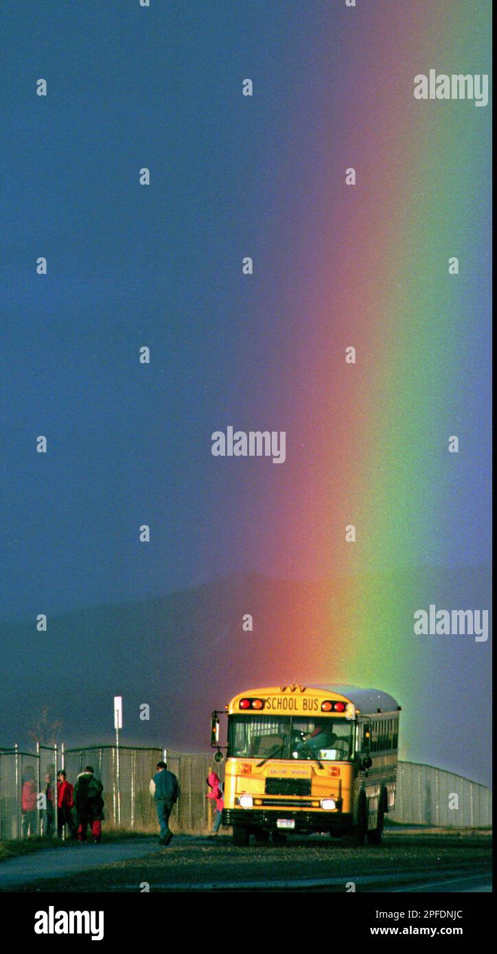 Students depart a school bus in Helena, Mont., under the glow of a ...