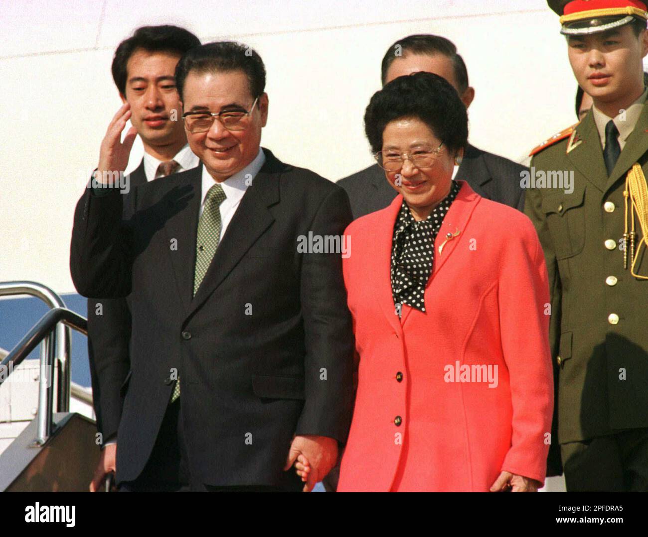 Holding a hand of his wife Zhu Lin, Chinese Premier Li Peng waves upon ...