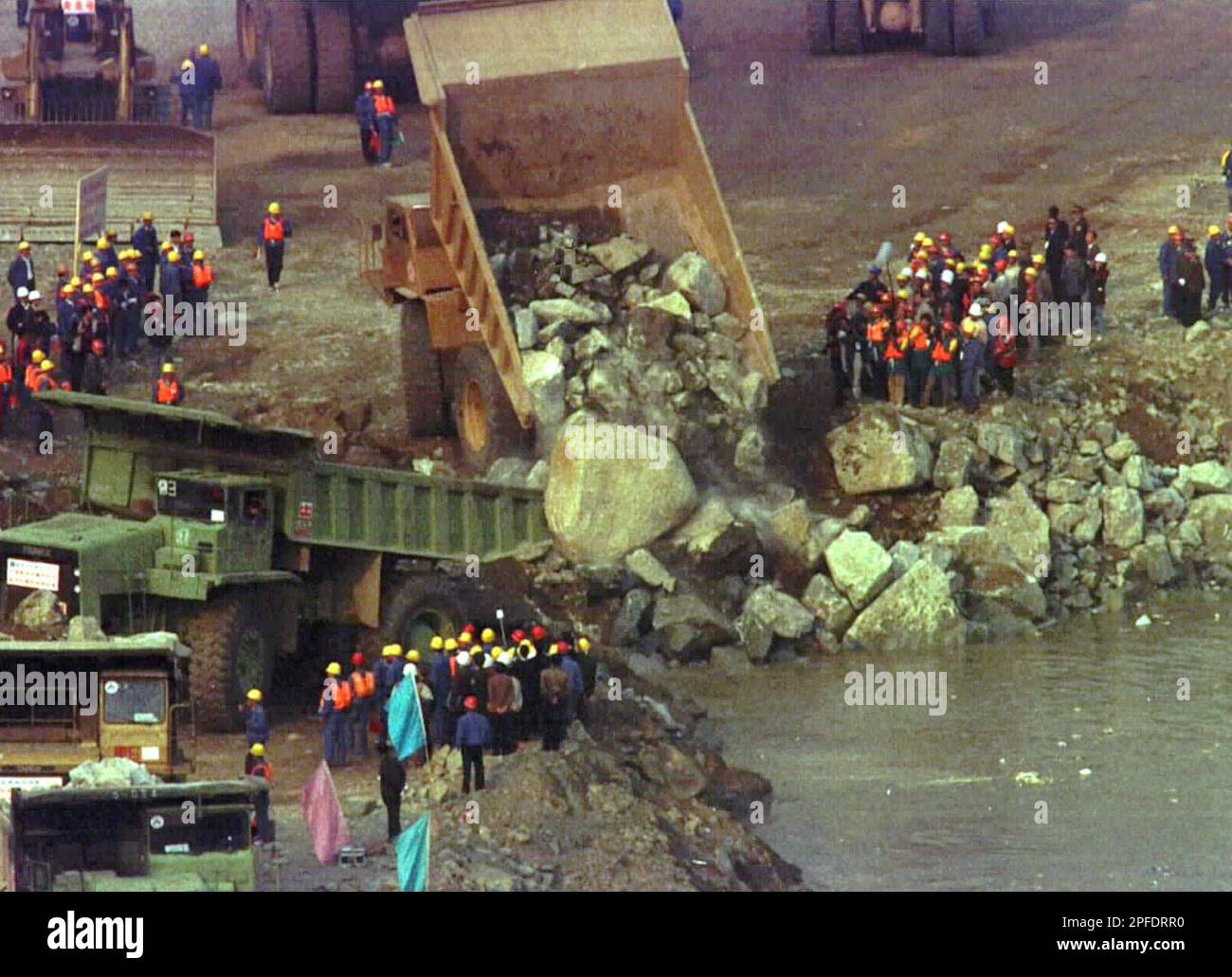 Trucks dump rocks into the Yantze River to close the final section of a ...