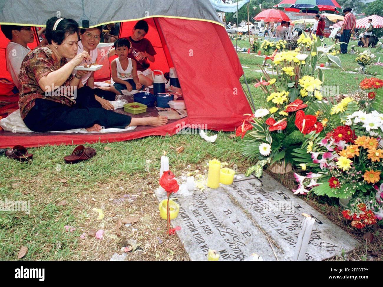 A Filipino Christian family eat their lunch beside the tombs of their ...