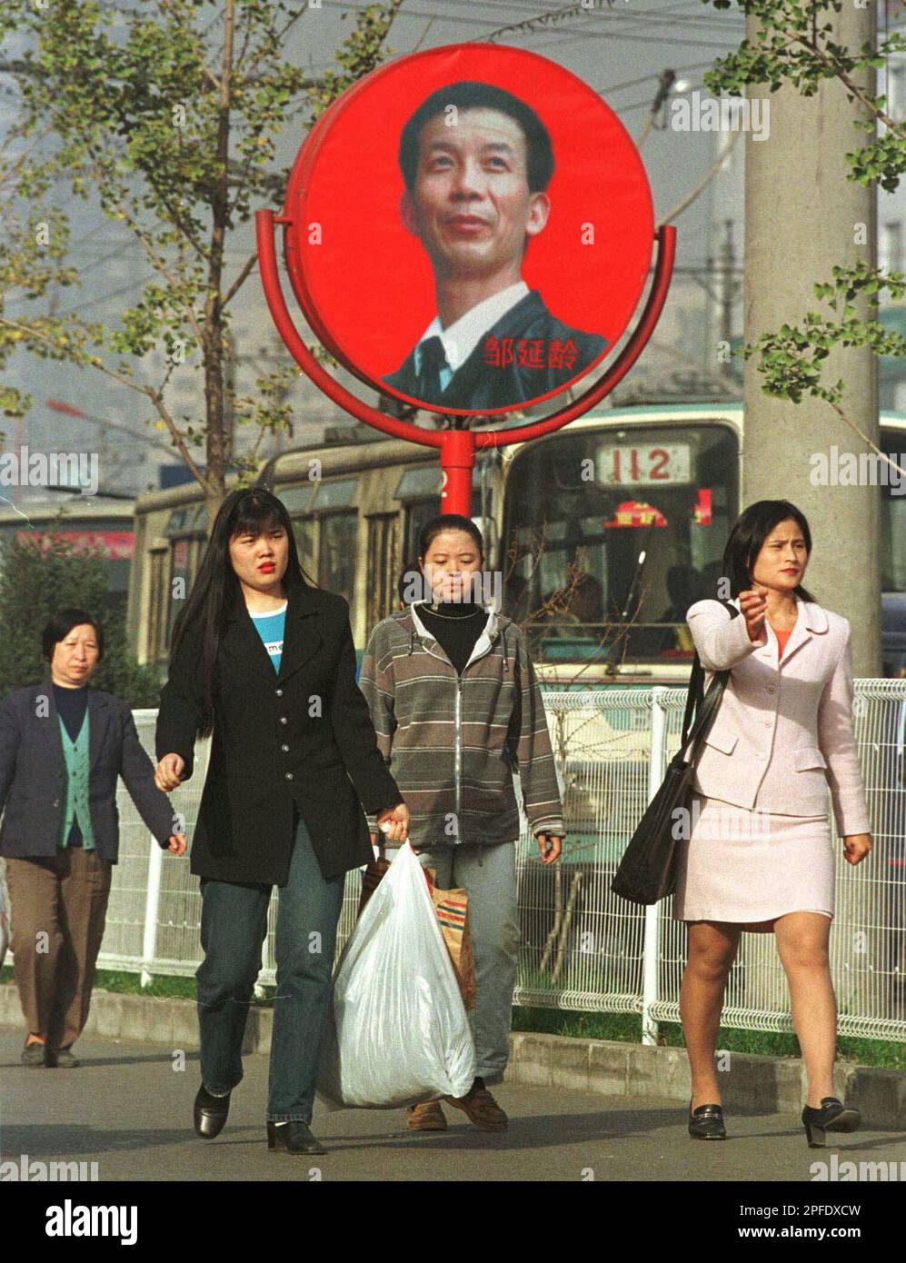 Communters walk past a portrait of Chinese test pilot Zou Yanling on a ...