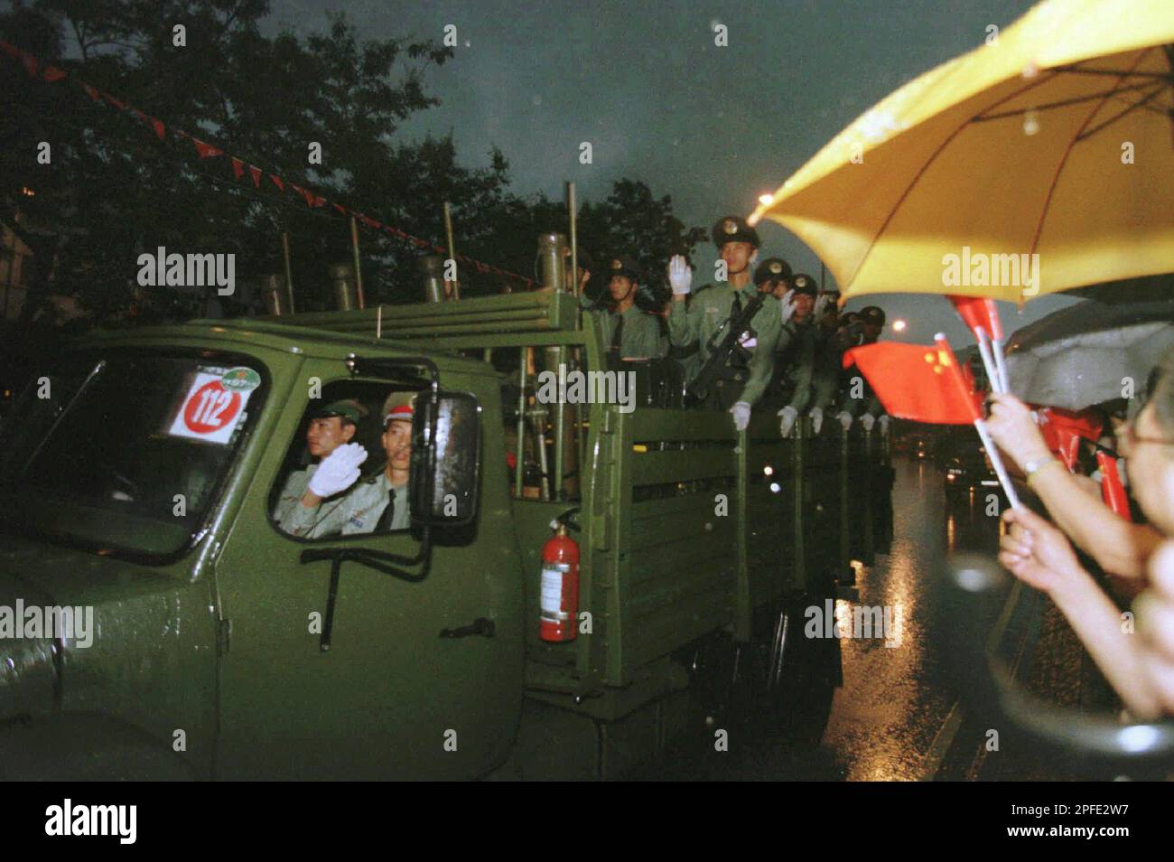 A convoy of trucks carrying the People's Liberation Army drive past ...