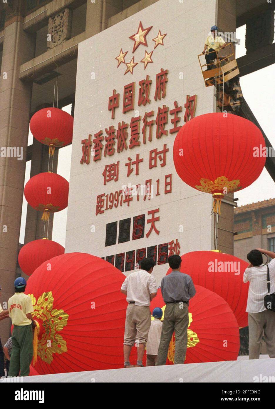 Chinese workers use a crane to hang huge lantern beside the clock which ...
