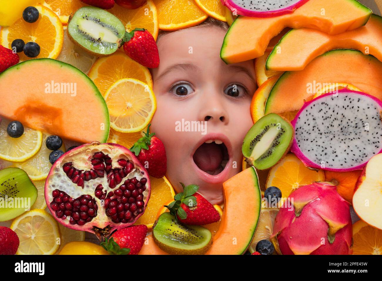 Kid tasting fruits. Excited kids face with mix of strawberry, blueberry ...