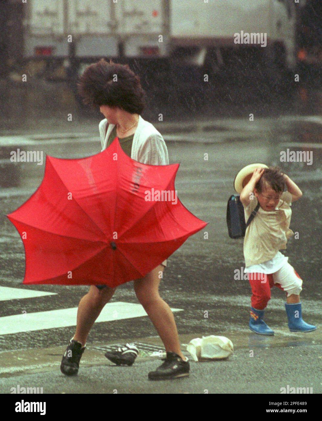 A mother and child struggle in torrential rain on a crossing in ...