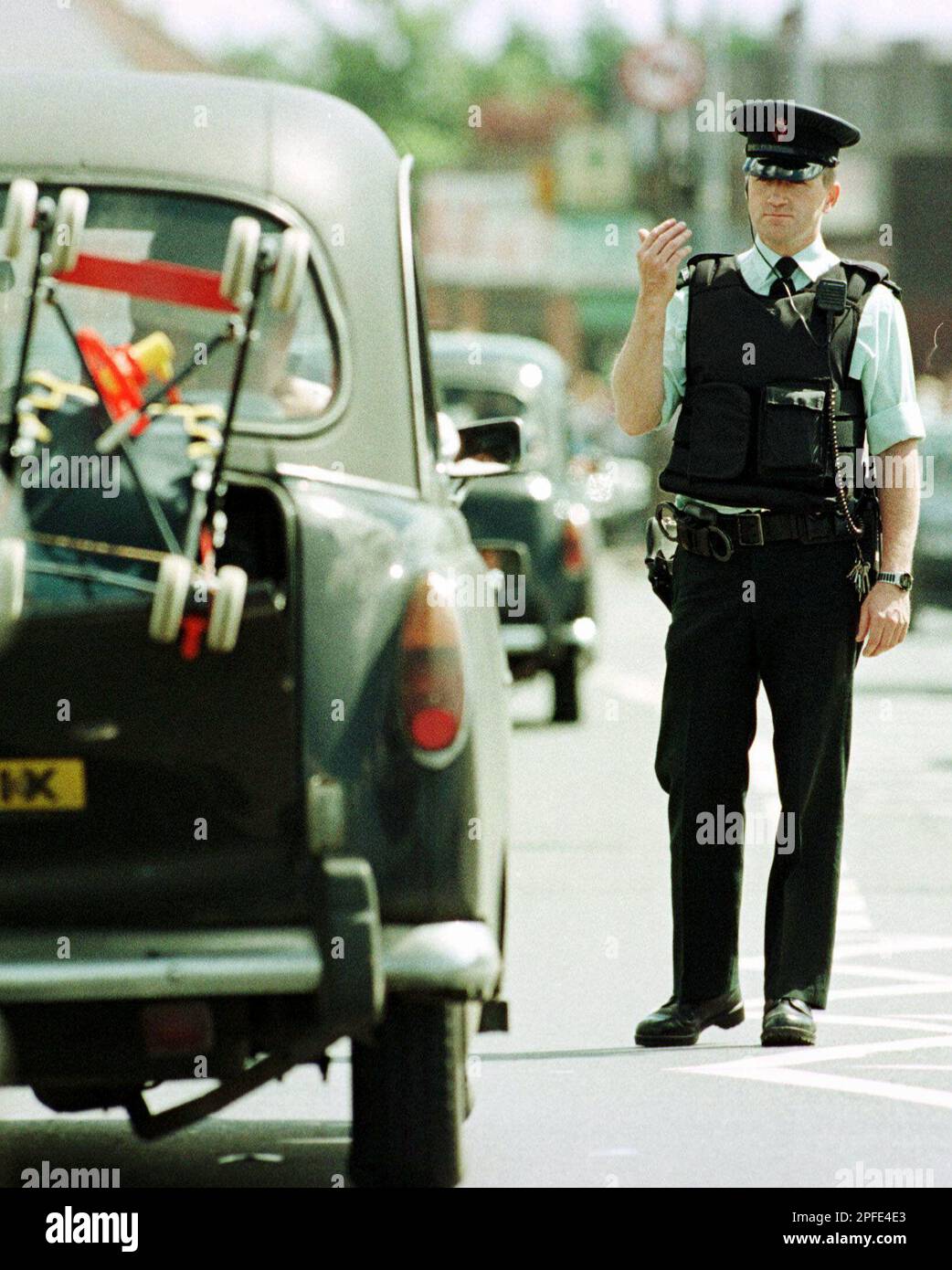 A Royal Ulster Constabulary police officer stops traffic on the main ...