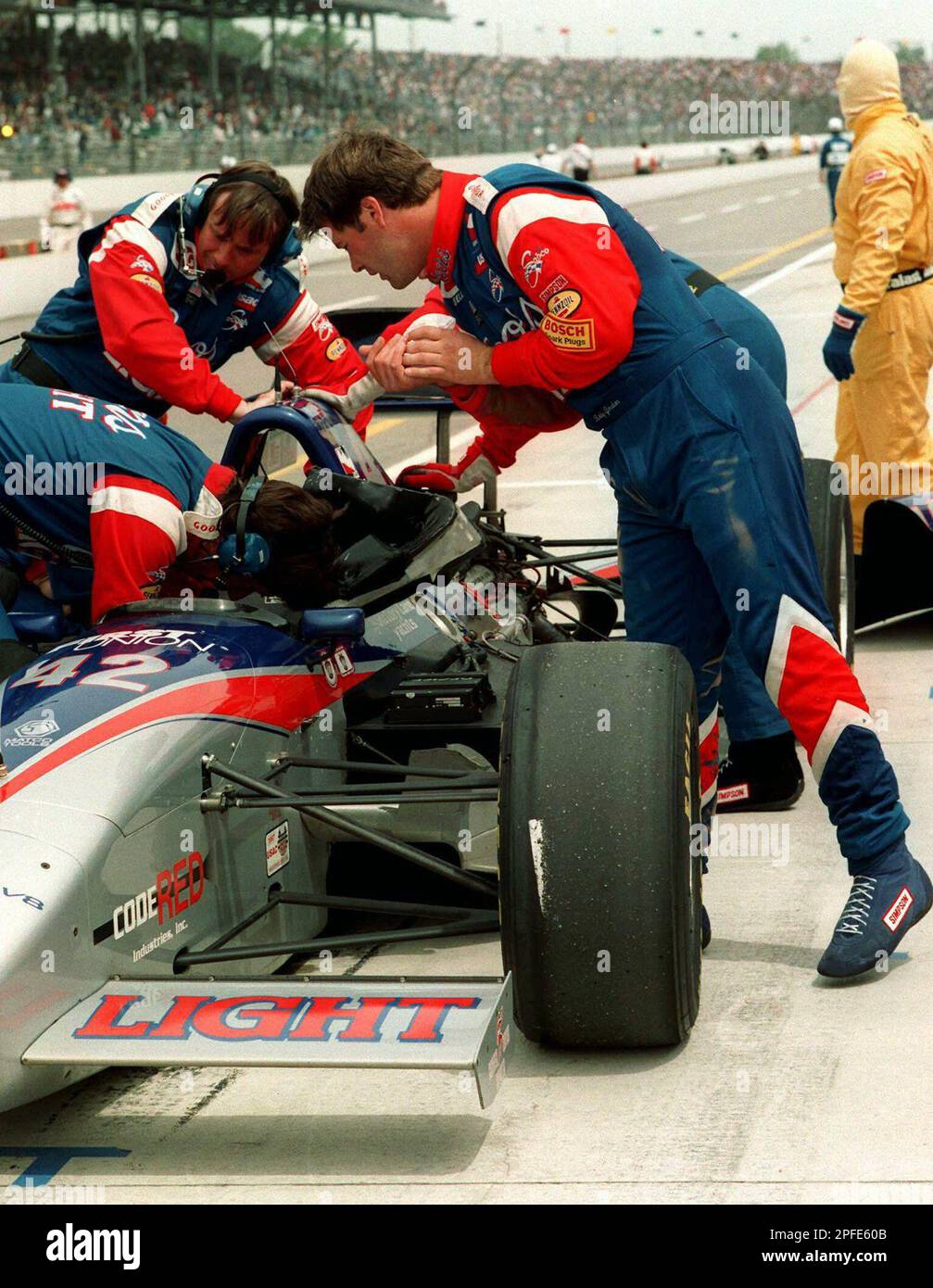 Robby Gordon, right, rubs his burned hands as crew members look at his ...