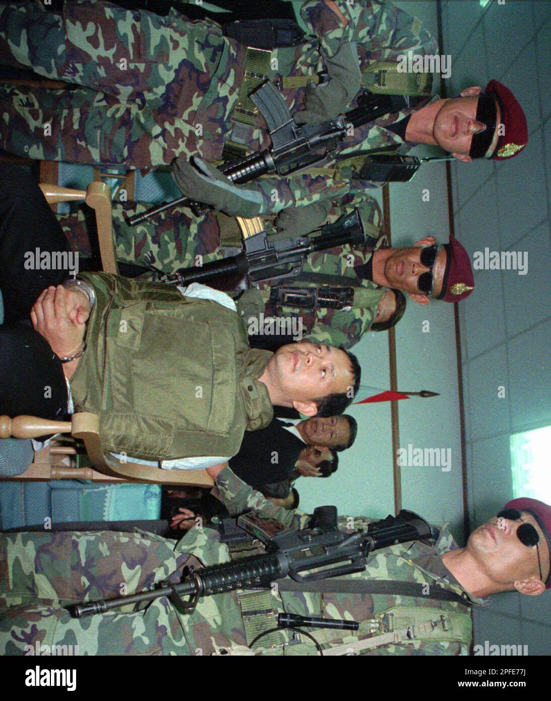 Li Yun Chung is handcuffed and surrounded by Thai soldiers during a ...