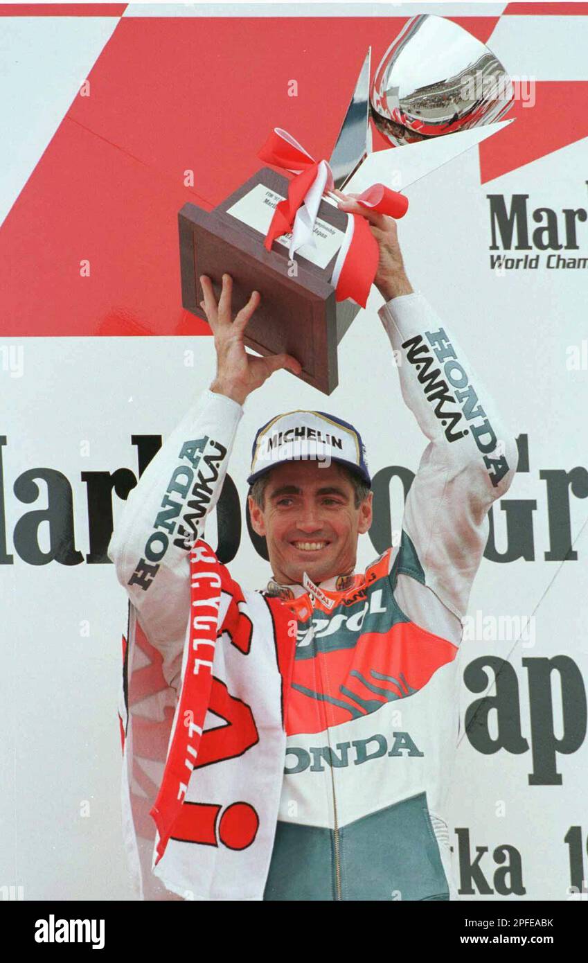 Repsol Honda 500cc rider Michael Doohan of Australia lifts a trophy of ...