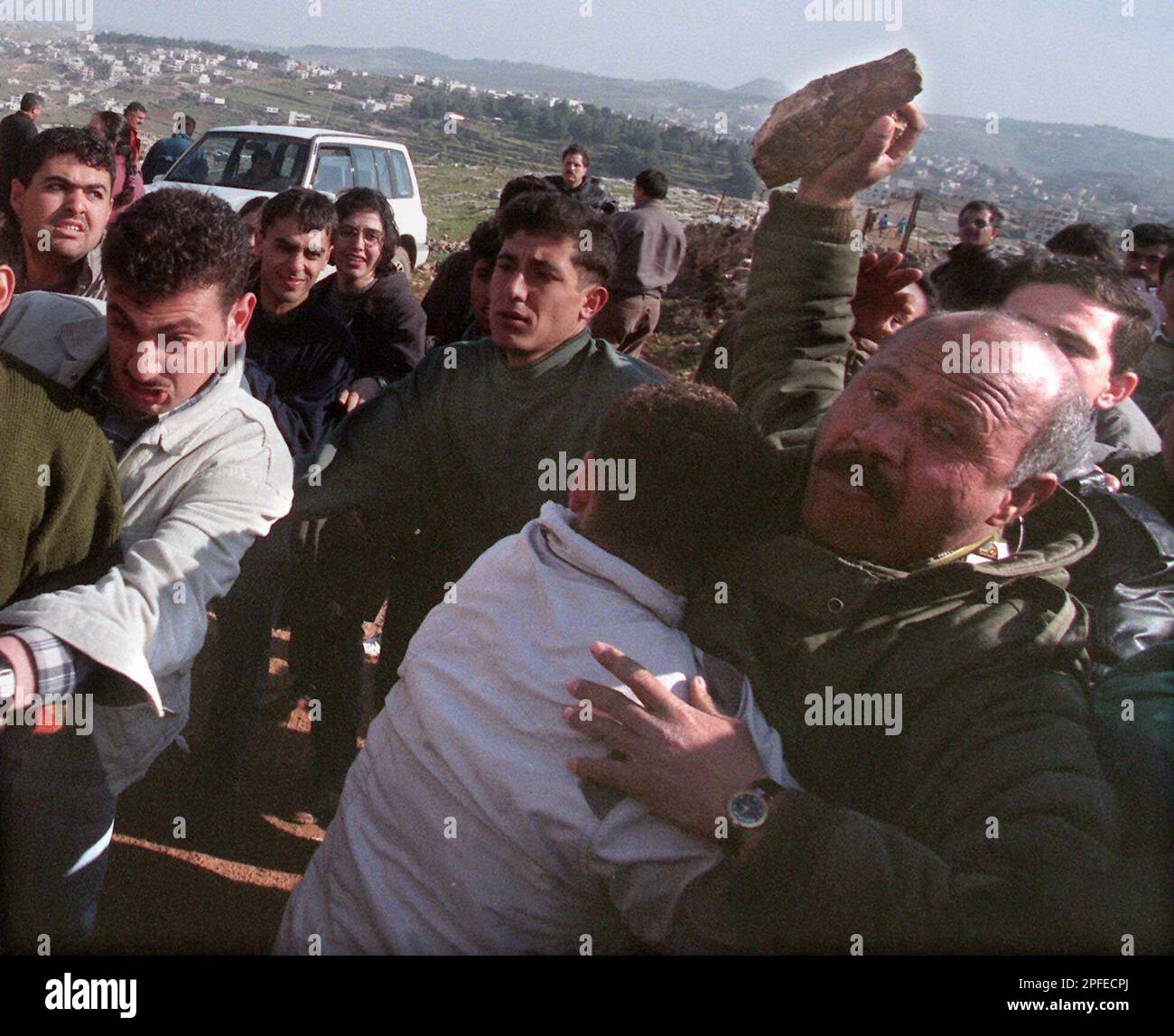 A heated Palestinian demonstrator is restrained by another man from ...