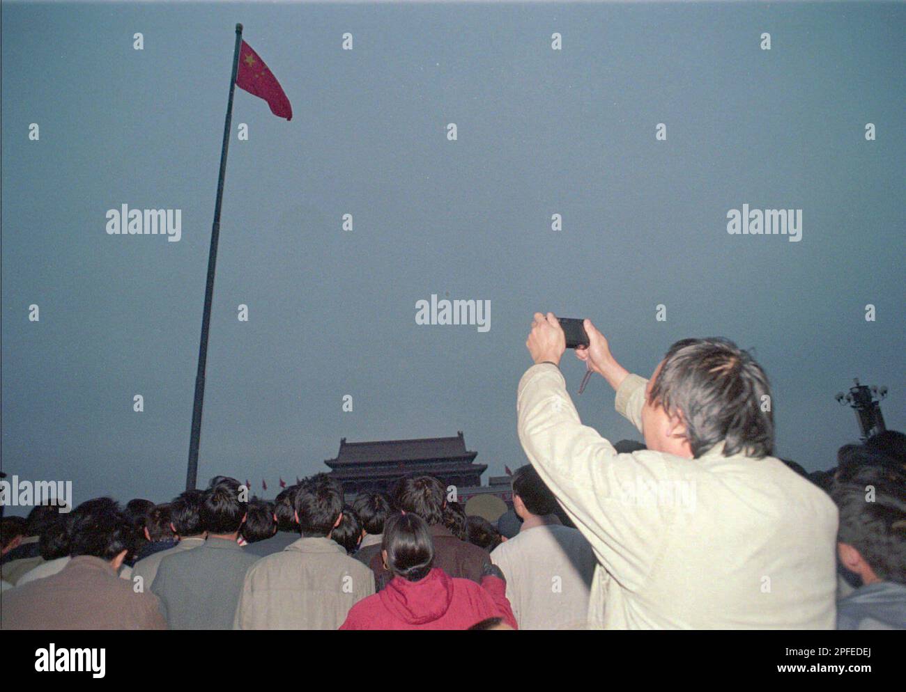 A man takes a photo of the last stage of the daily ritual of raising ...