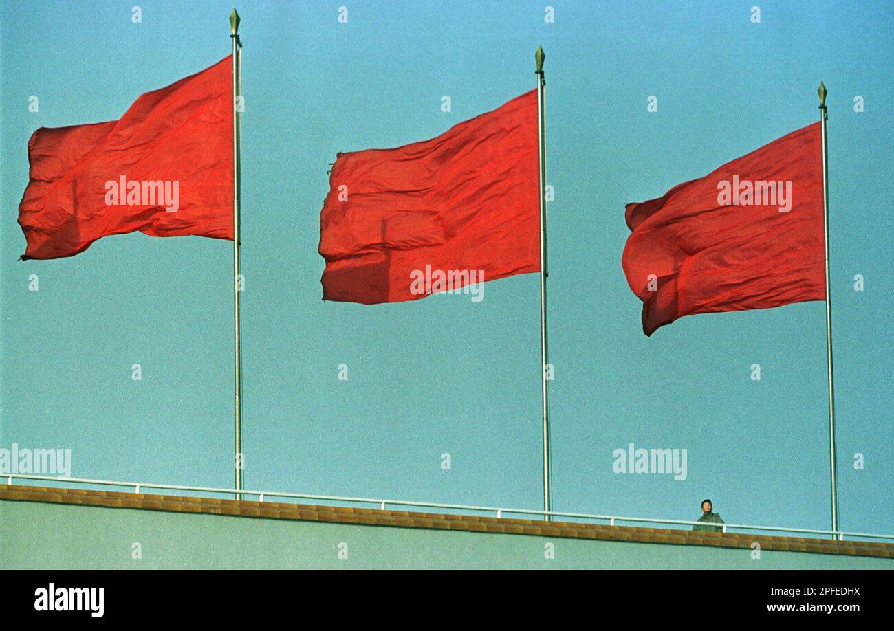 A police guard is dwarfed by three huge red flags on Tiananmen Gate in ...
