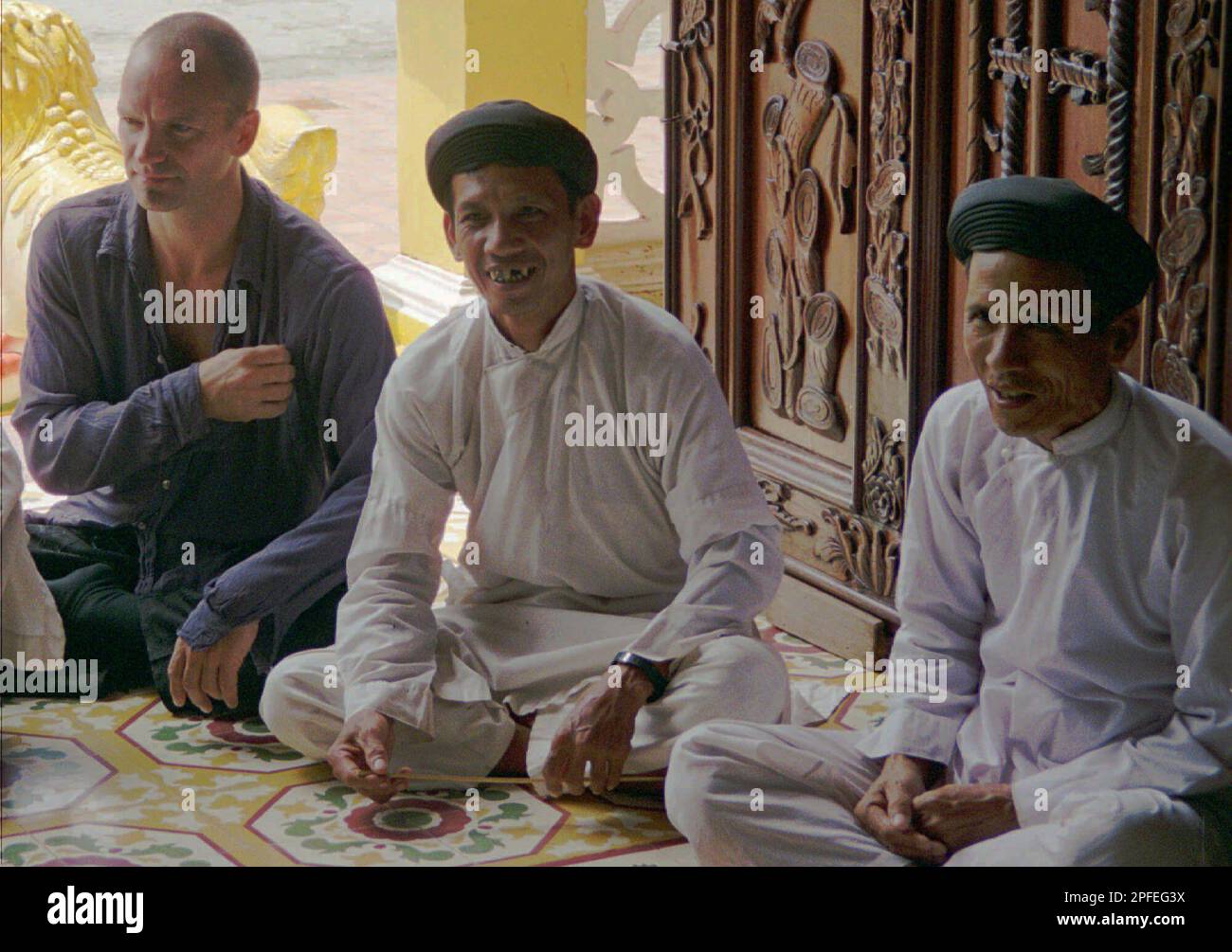 Rock star Sting, left, sits with monks during a visit to the Cao Dai ...
