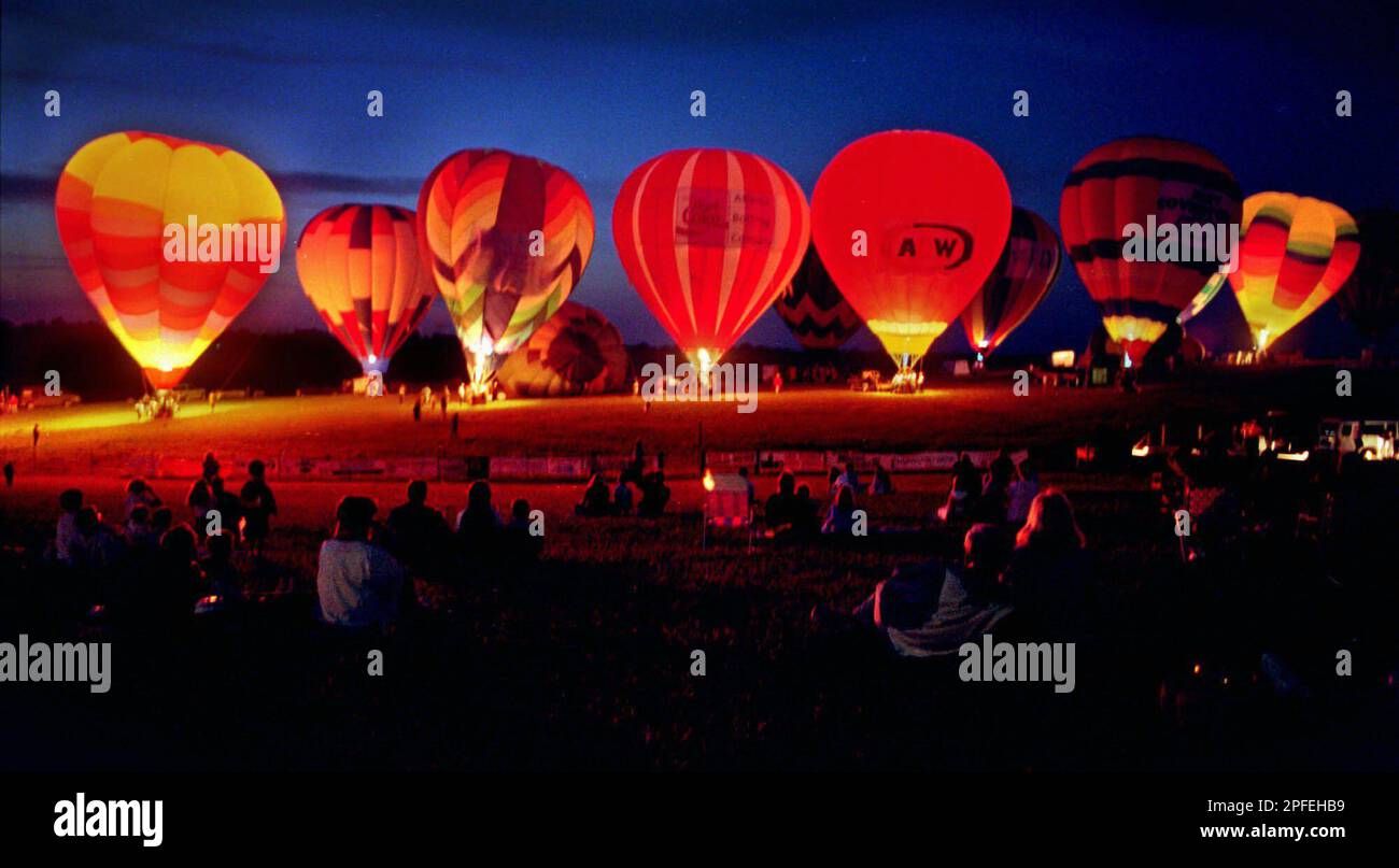 Spectators watch as the hot air balloons light up the evening sky for ...