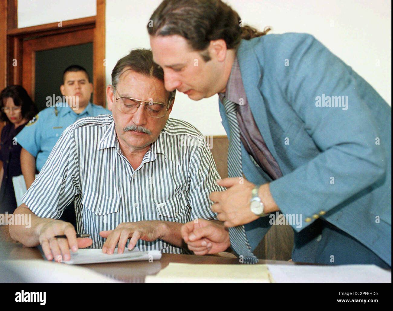 Signing his plea bargain, former Gallup High School Principal Charles Johnson, left, who was ...