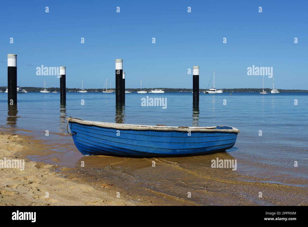 Blue row boat resting at the water’s edge on main beach Coochiemudlo ...