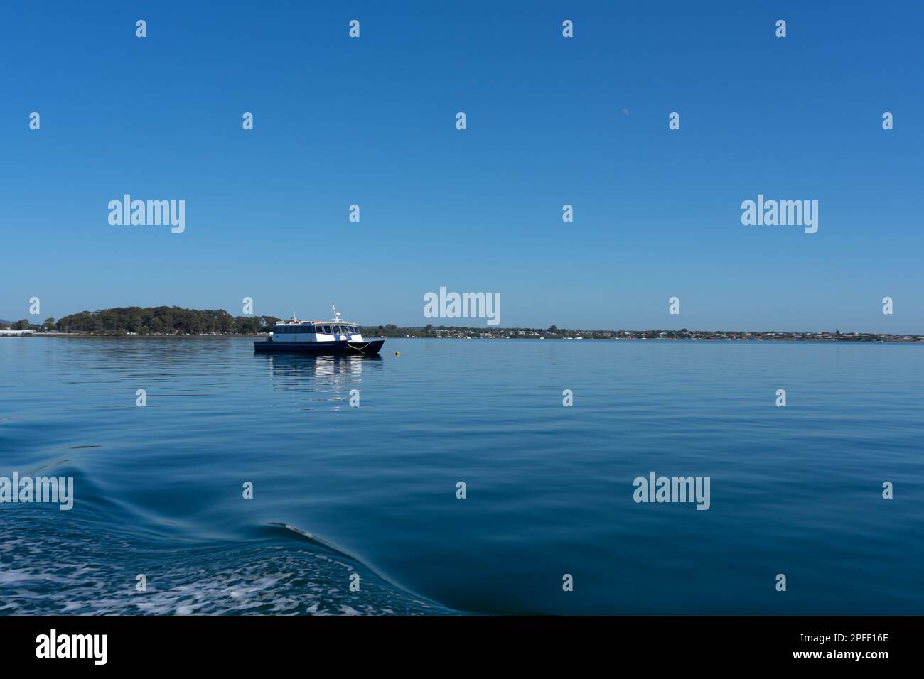 View from a boat, looking past an anchored passenger ferry back toward ...