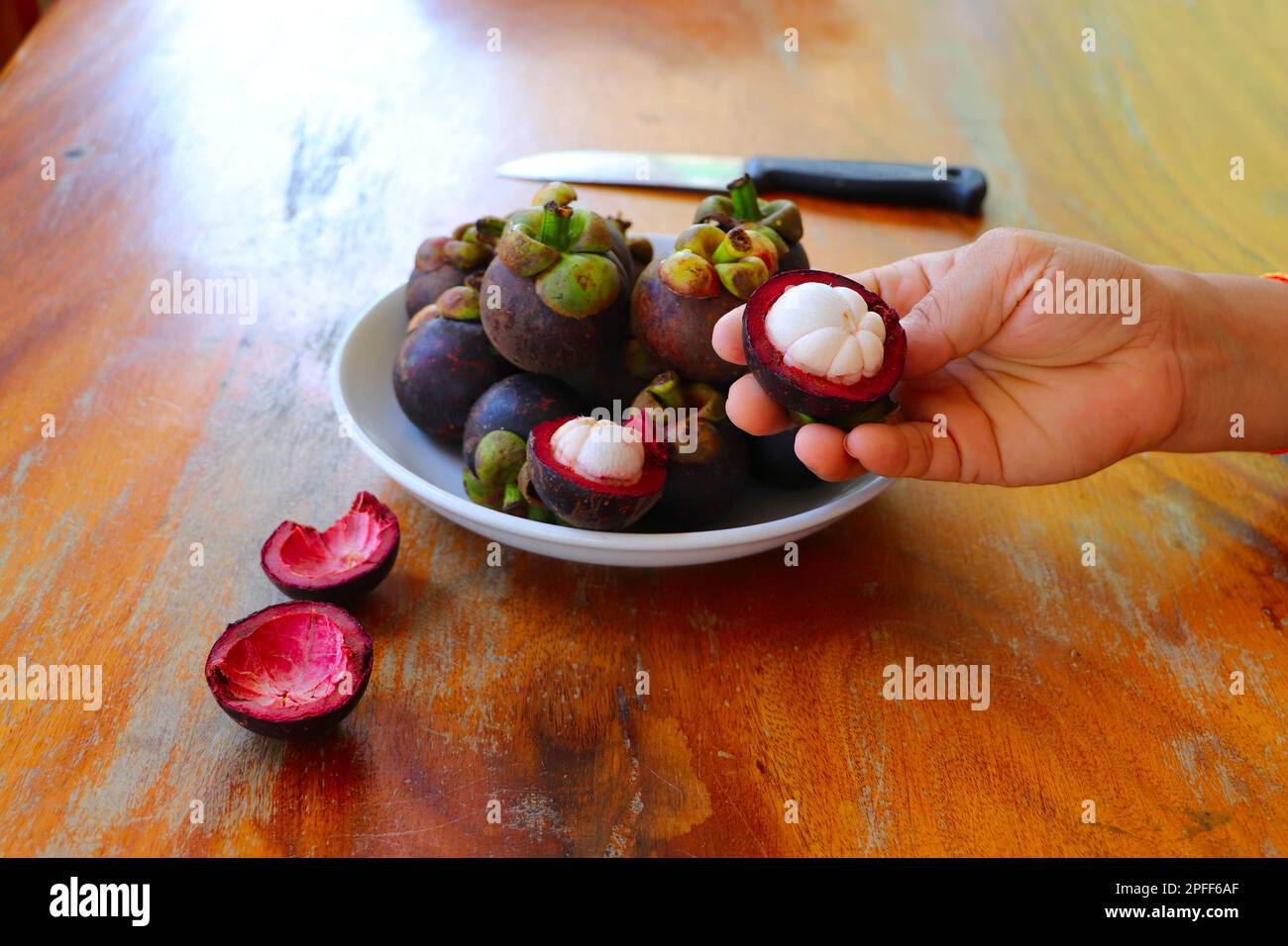 Close up of woman's hands cutting fresh mangosteens. Slicing and ...