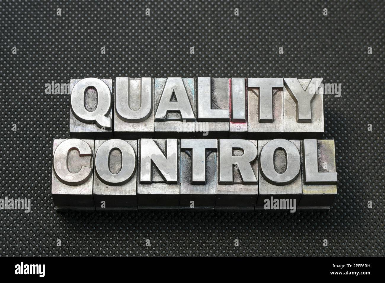quality control phrase made from metallic letterpress blocks on black ...