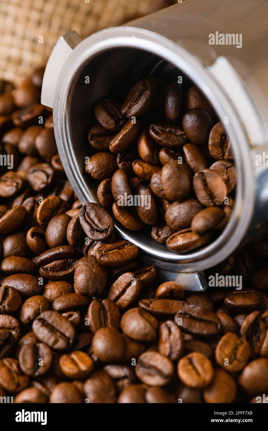 Roasted espresso coffee beans thrown in wooden table with metal carob ...