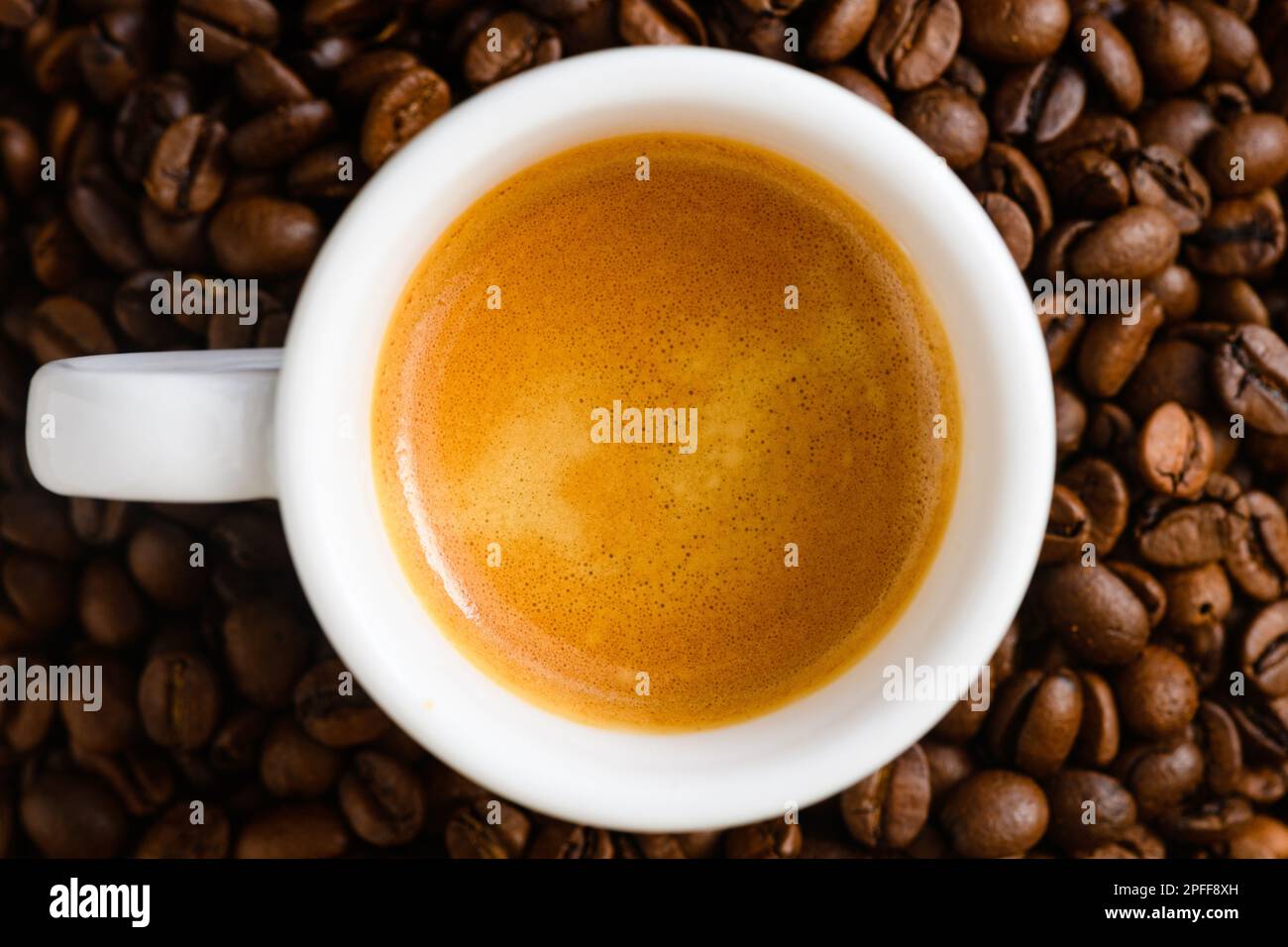 Top view of brewed espresso in cup at whole roasted coffee beans ...