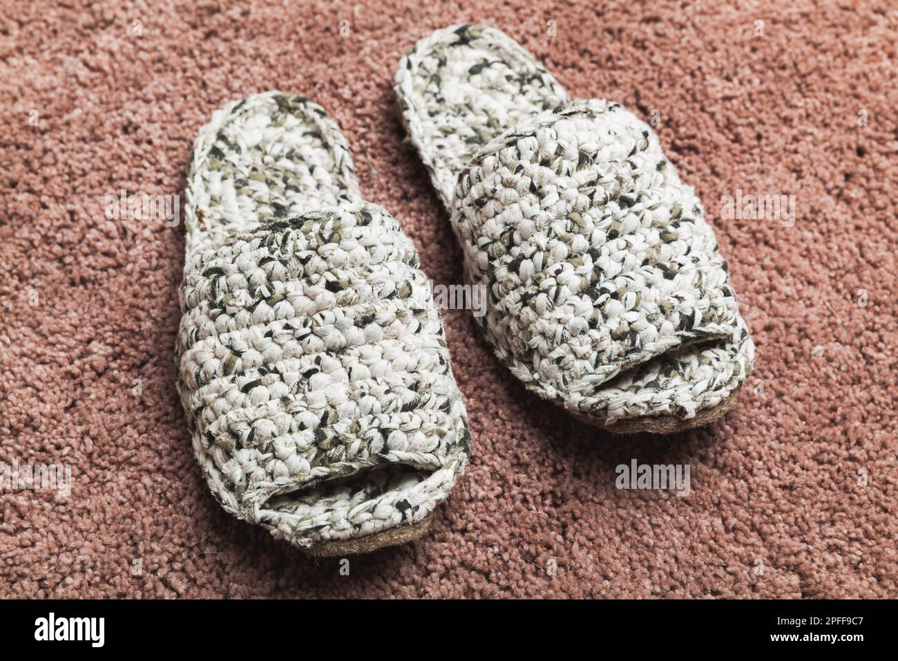 White knitted handmade slippers stand on a red carpet, close-up photo ...
