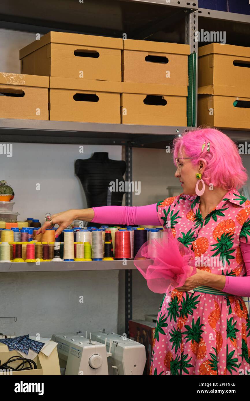 Dressmaker with pink hair and colorfull clothes choosing a thread Stock ...