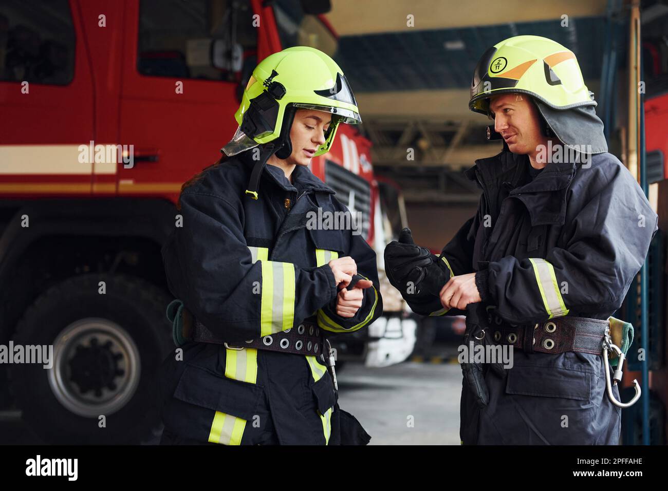 Male and female firefighters in protective uniform standing together ...