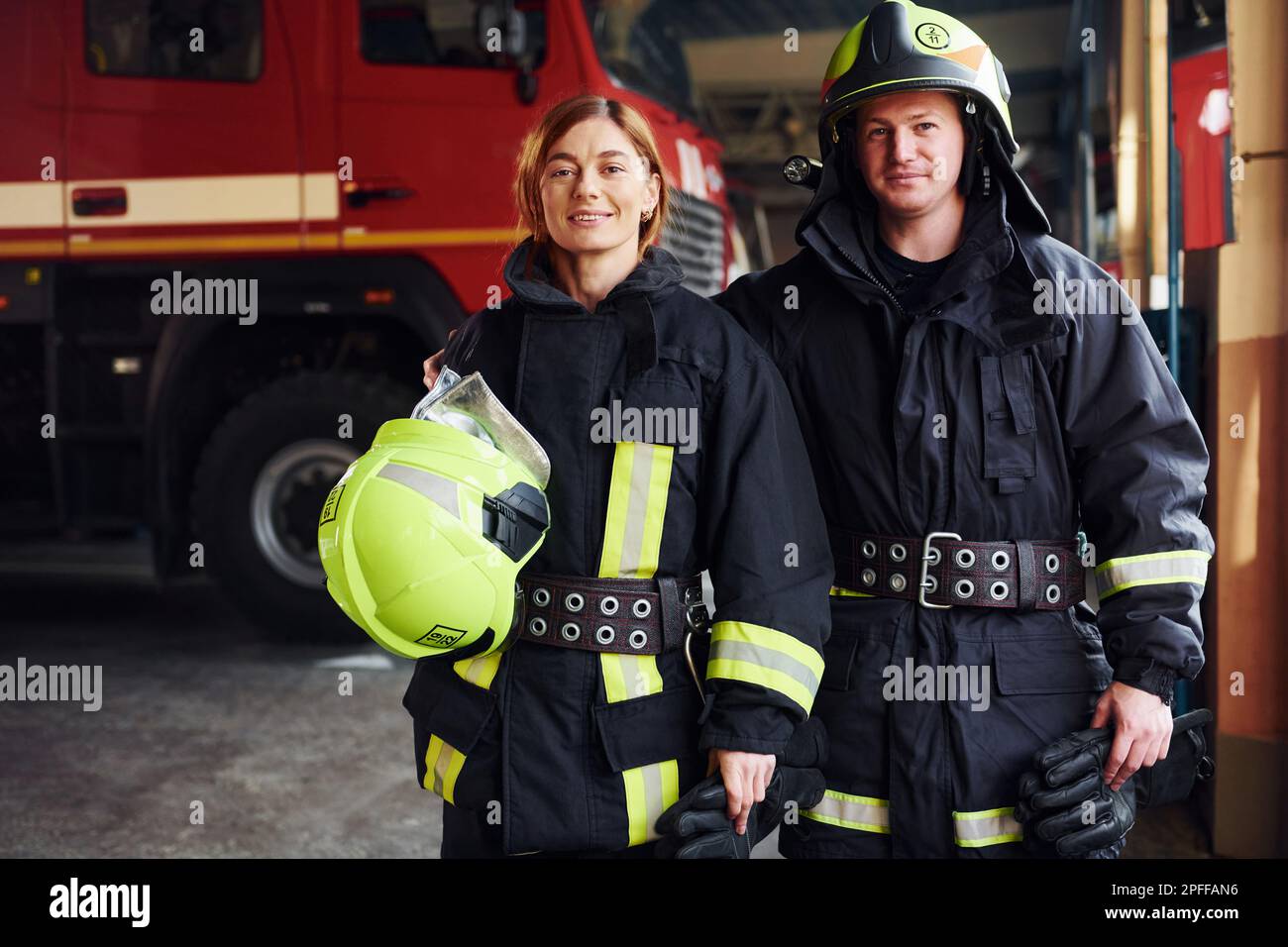 Male and female firefighters in protective uniform standing together ...