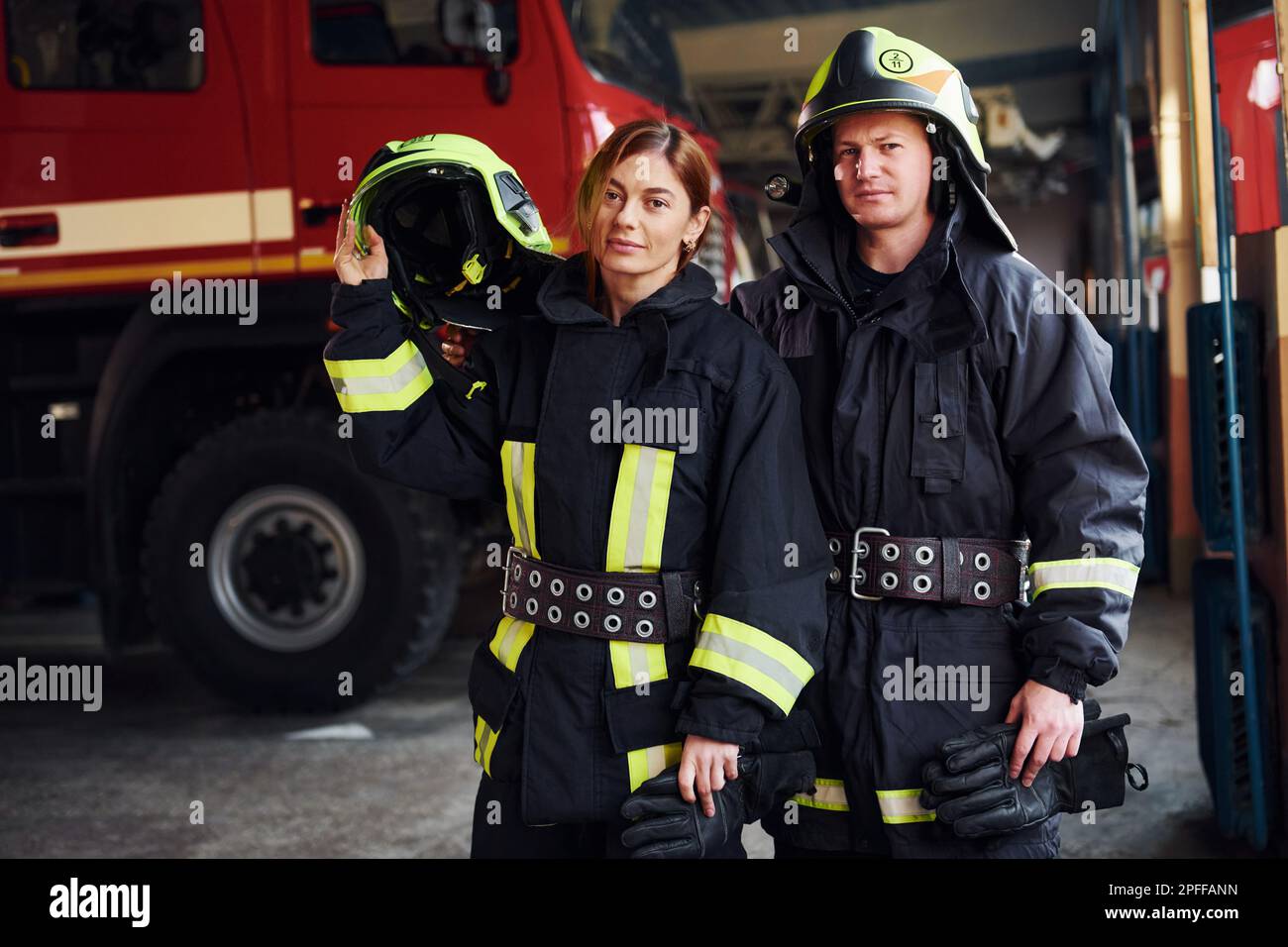 Male and female firefighters in protective uniform standing together ...