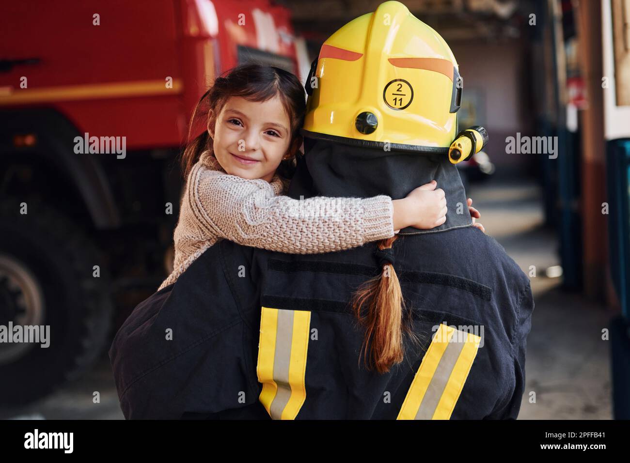 Happy little girl is with female firefighter in protective uniform ...