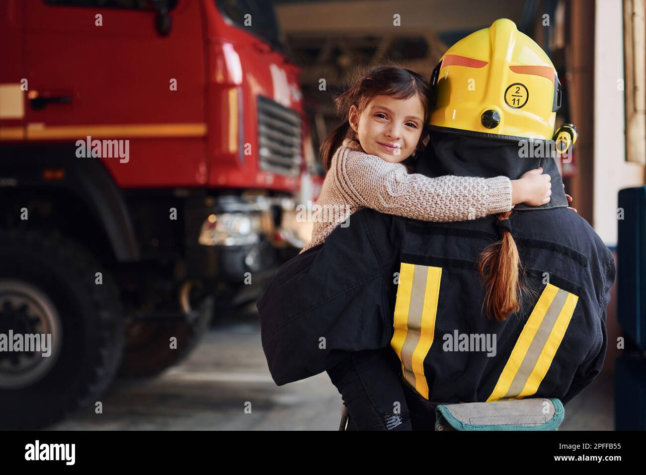 Happy little girl is with female firefighter in protective uniform ...