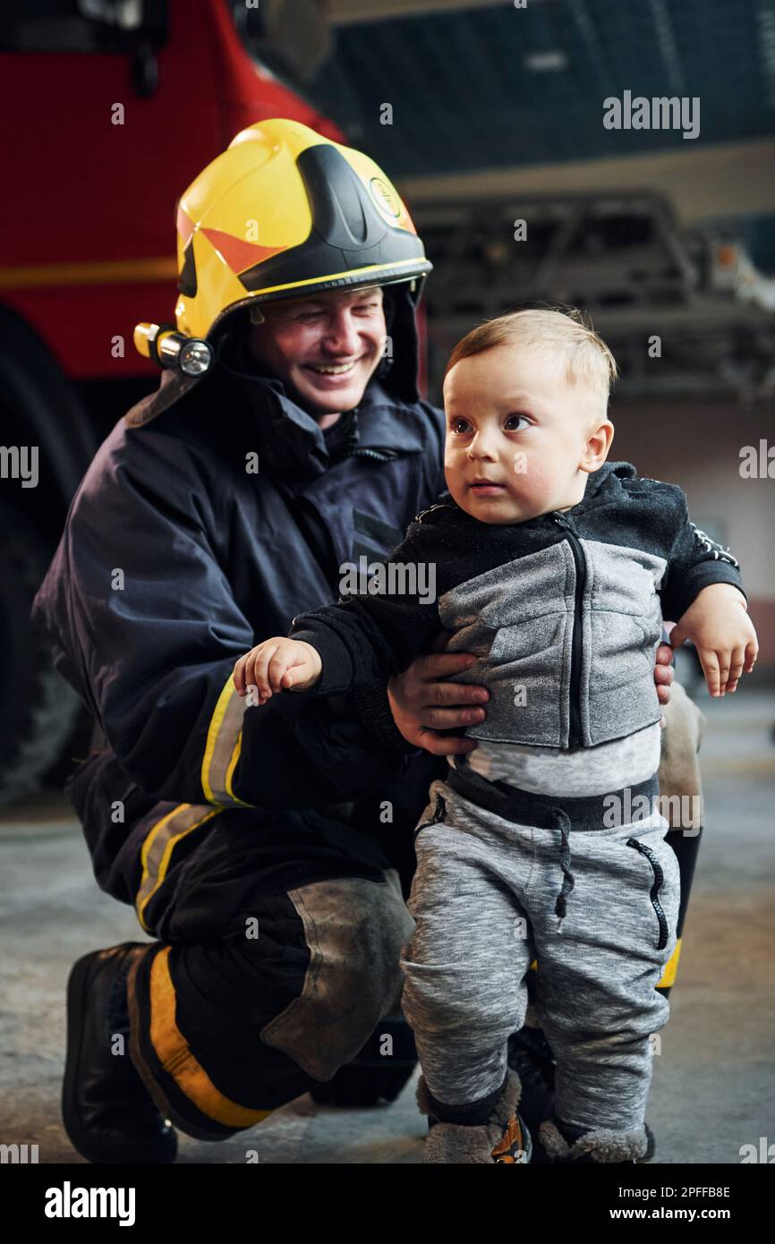 Cute little boy is with male firefighter in protective uniform Stock ...