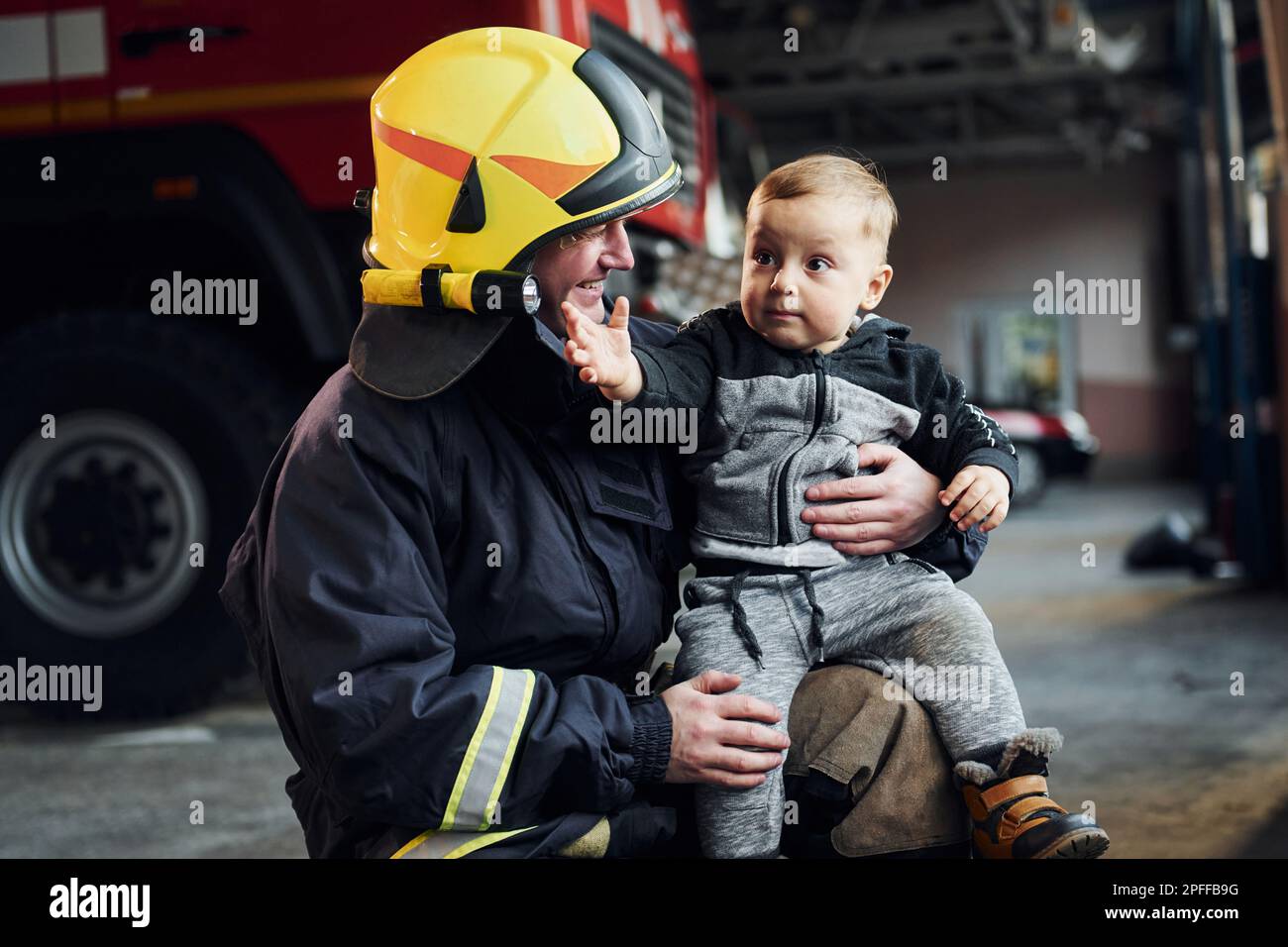 Cute little boy is with male firefighter in protective uniform Stock ...