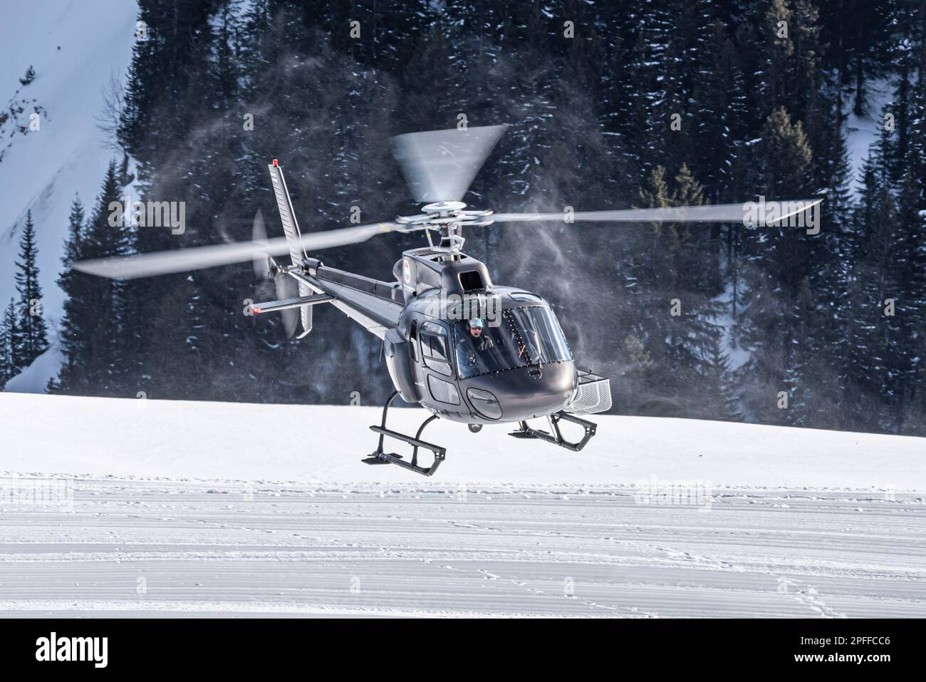 Grey Airbus Helicopters AS350 flying through the French Alps Stock ...