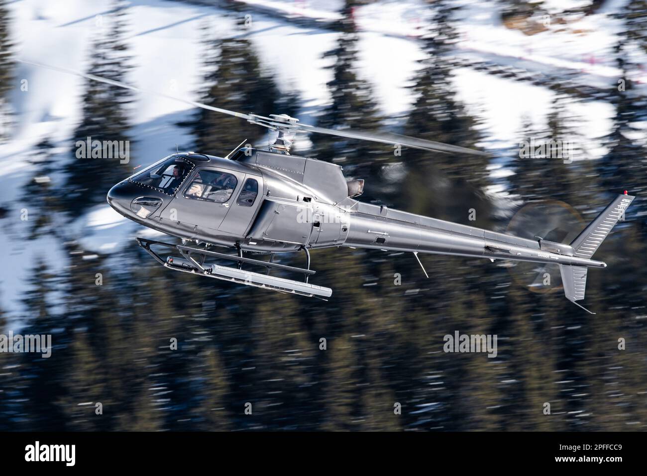 Grey Airbus Helicopters AS350 flying through the French Alps Stock ...