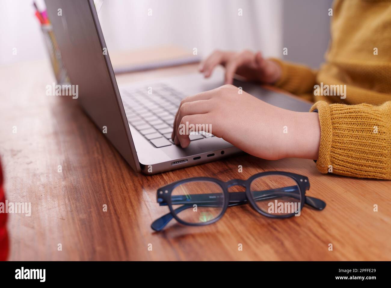 A close-up photo of a child's hands on a laptop, with the finger moving ...