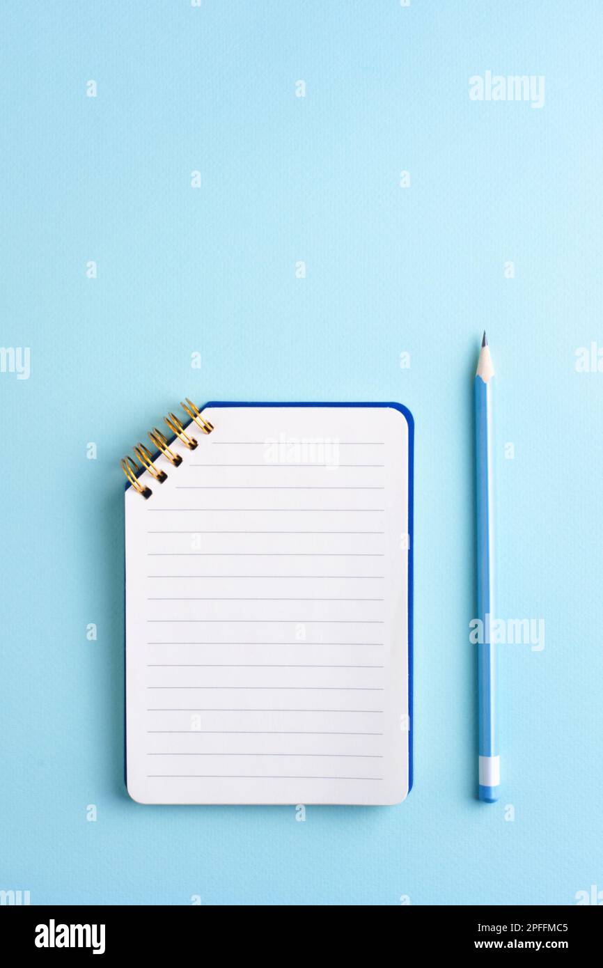 Vertical background with note book paper page and blue sharp pencil on ...