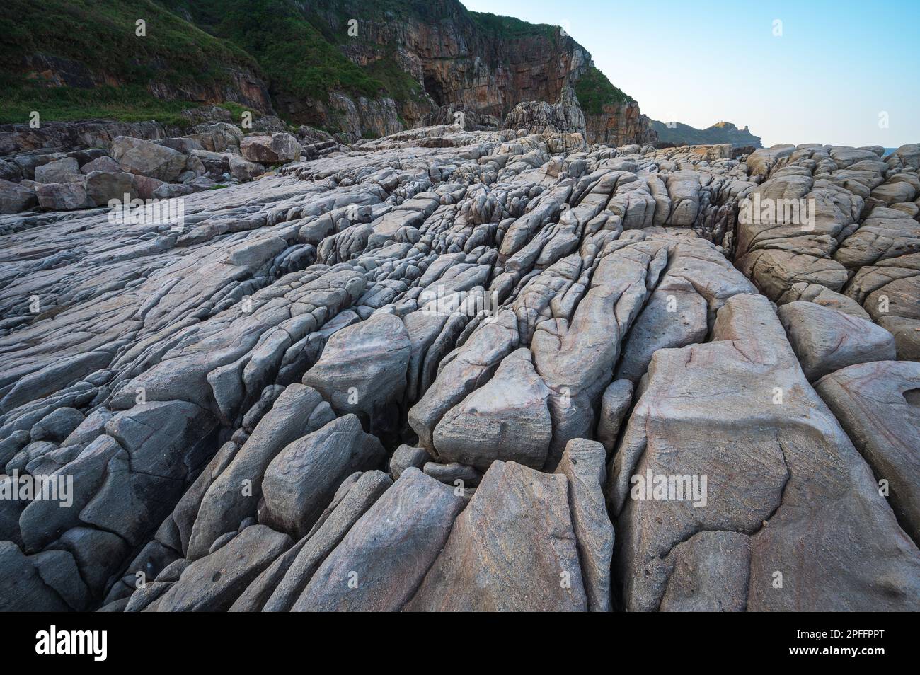Landscape of blue sea, mountains and textured rocks. Hazy dreamy sky ...