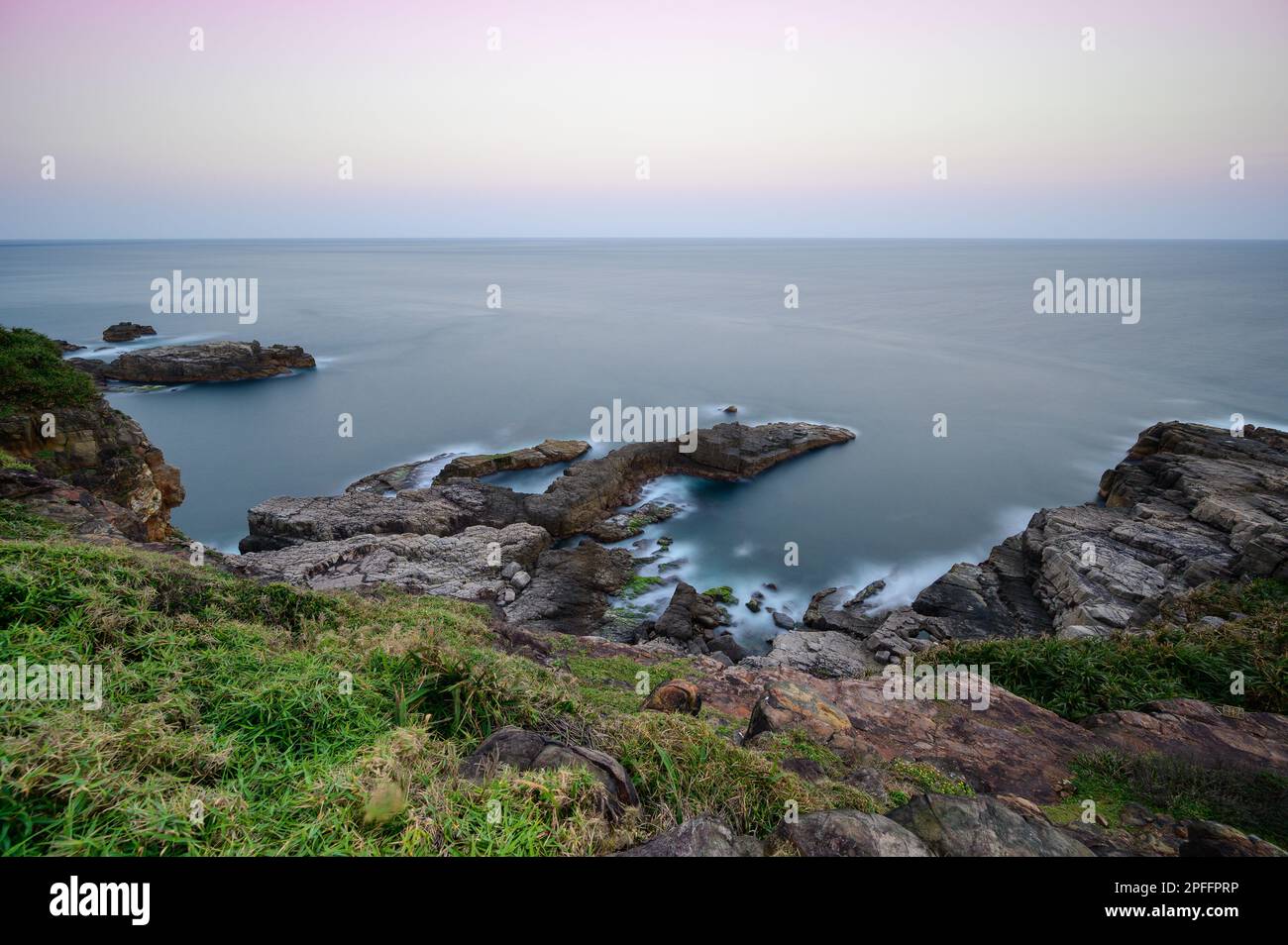Landscape of blue sea, mountains and textured rocks. Hazy dreamy sky ...