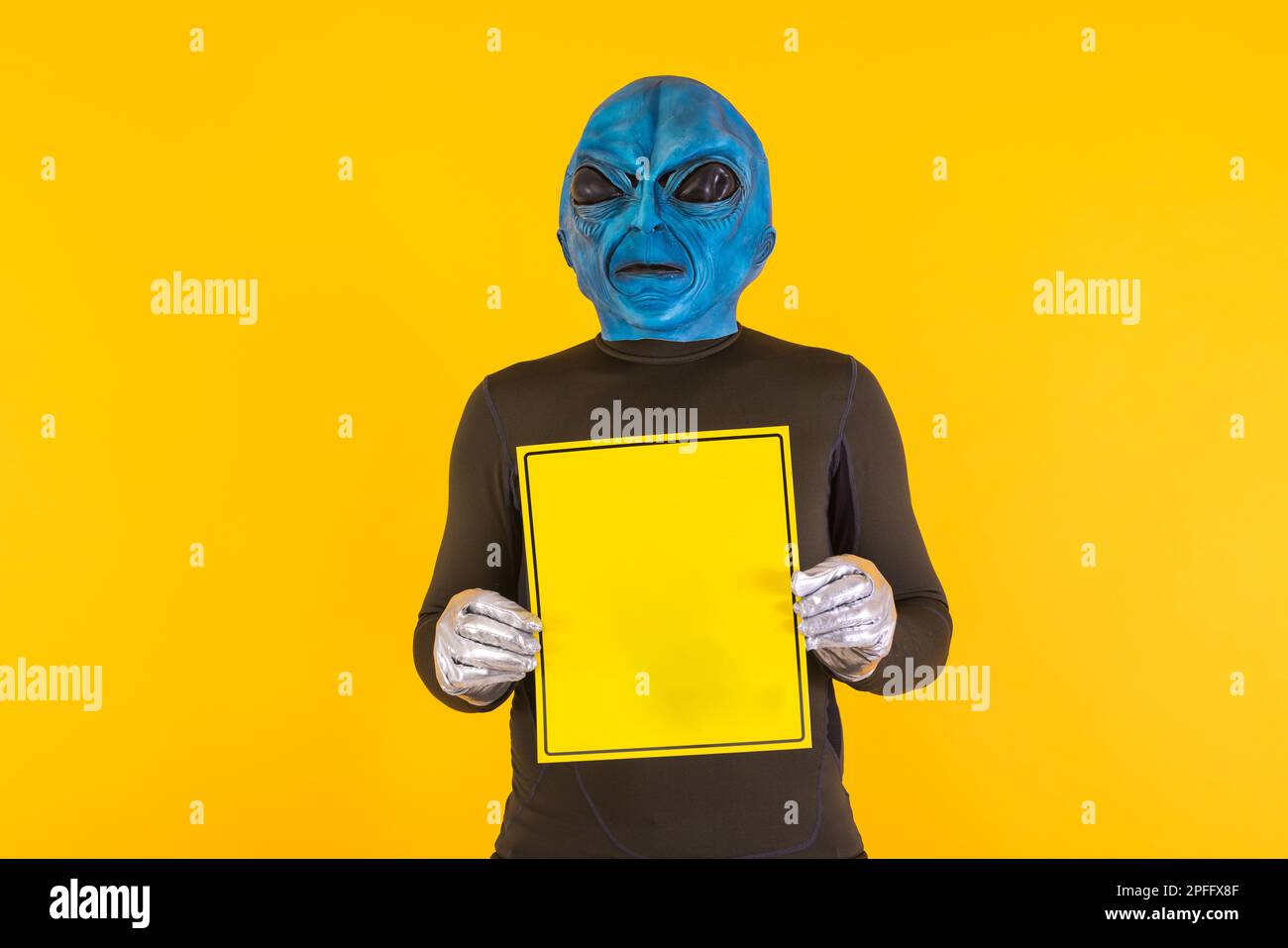 Man with alien mask with a blue head, holding a yellow sign. Concept of ...