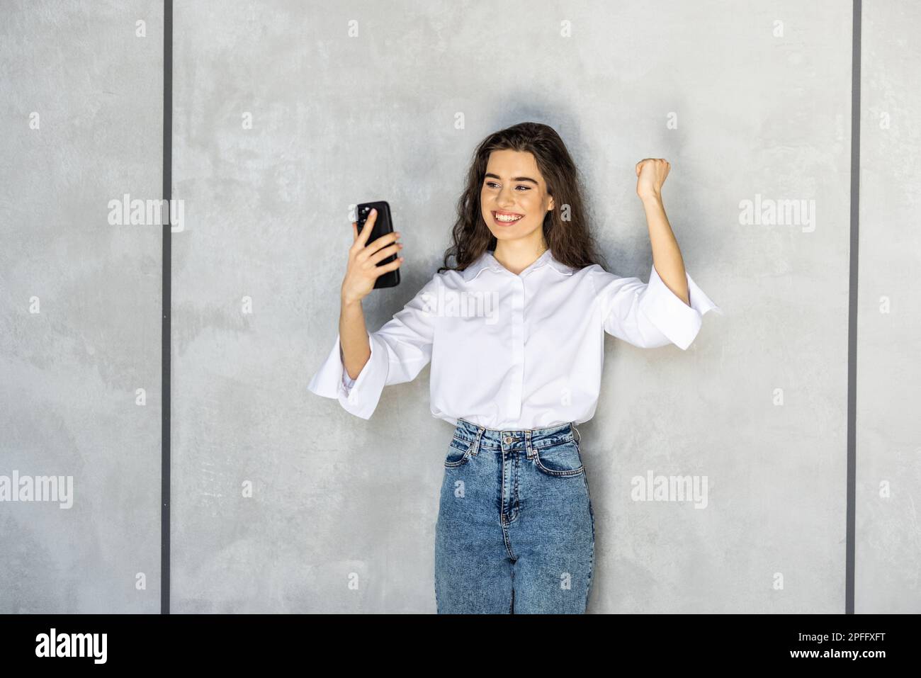 Excited young euphoric girl winner holding cell phone screaming with ...