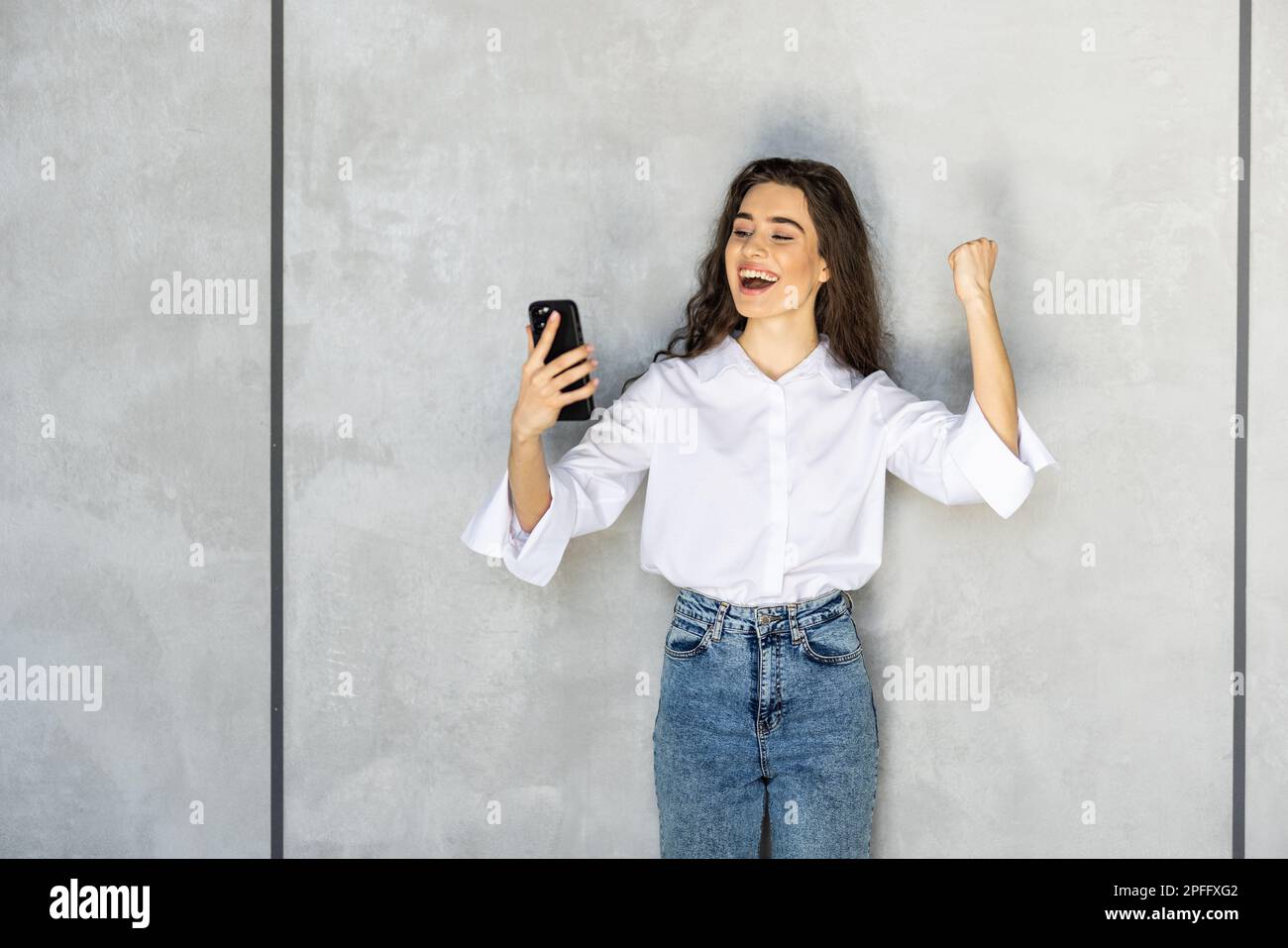 Excited young euphoric girl winner holding cell phone screaming with ...