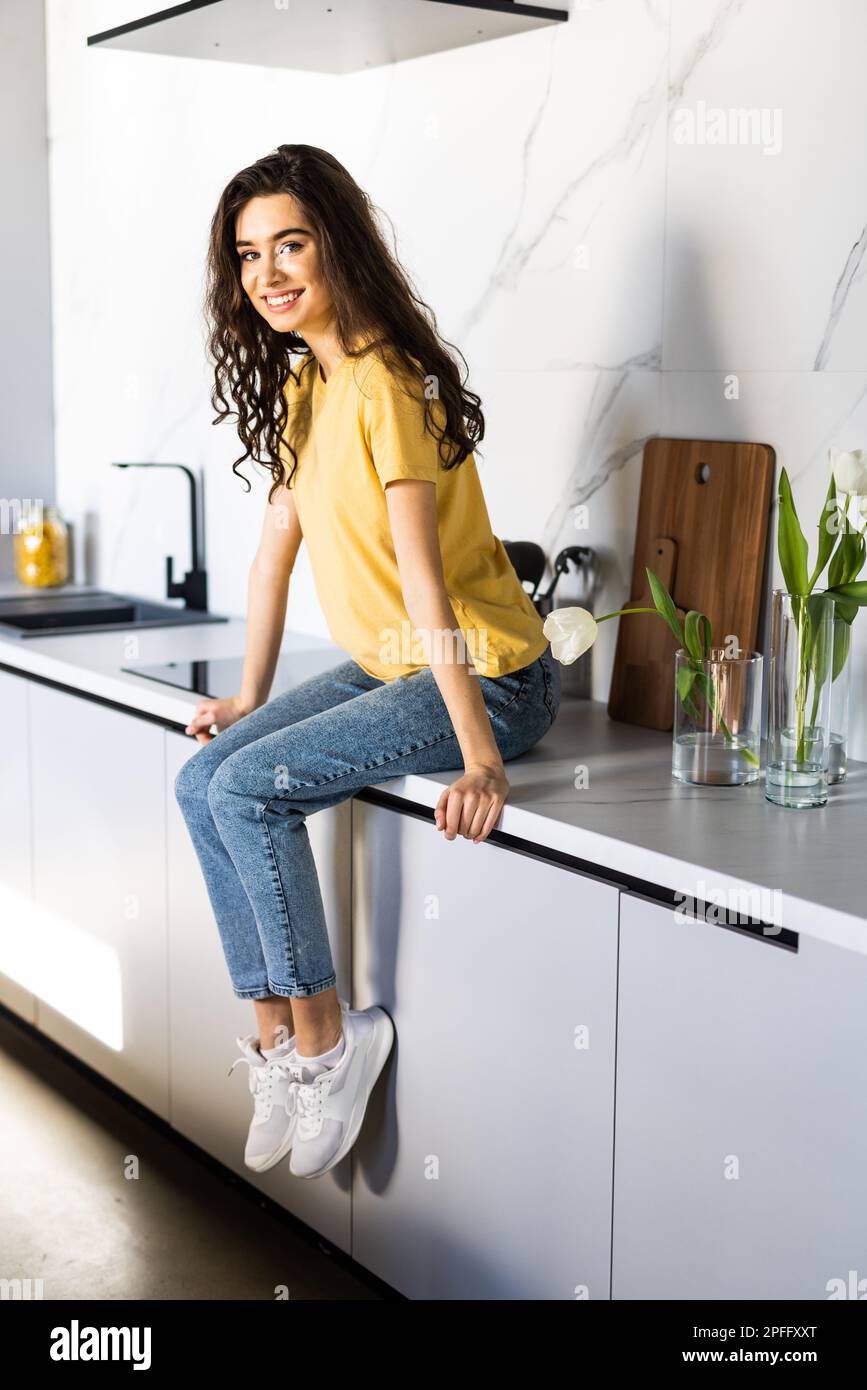 Young woman sitting on the kitchens counter Stock Photo - Alamy