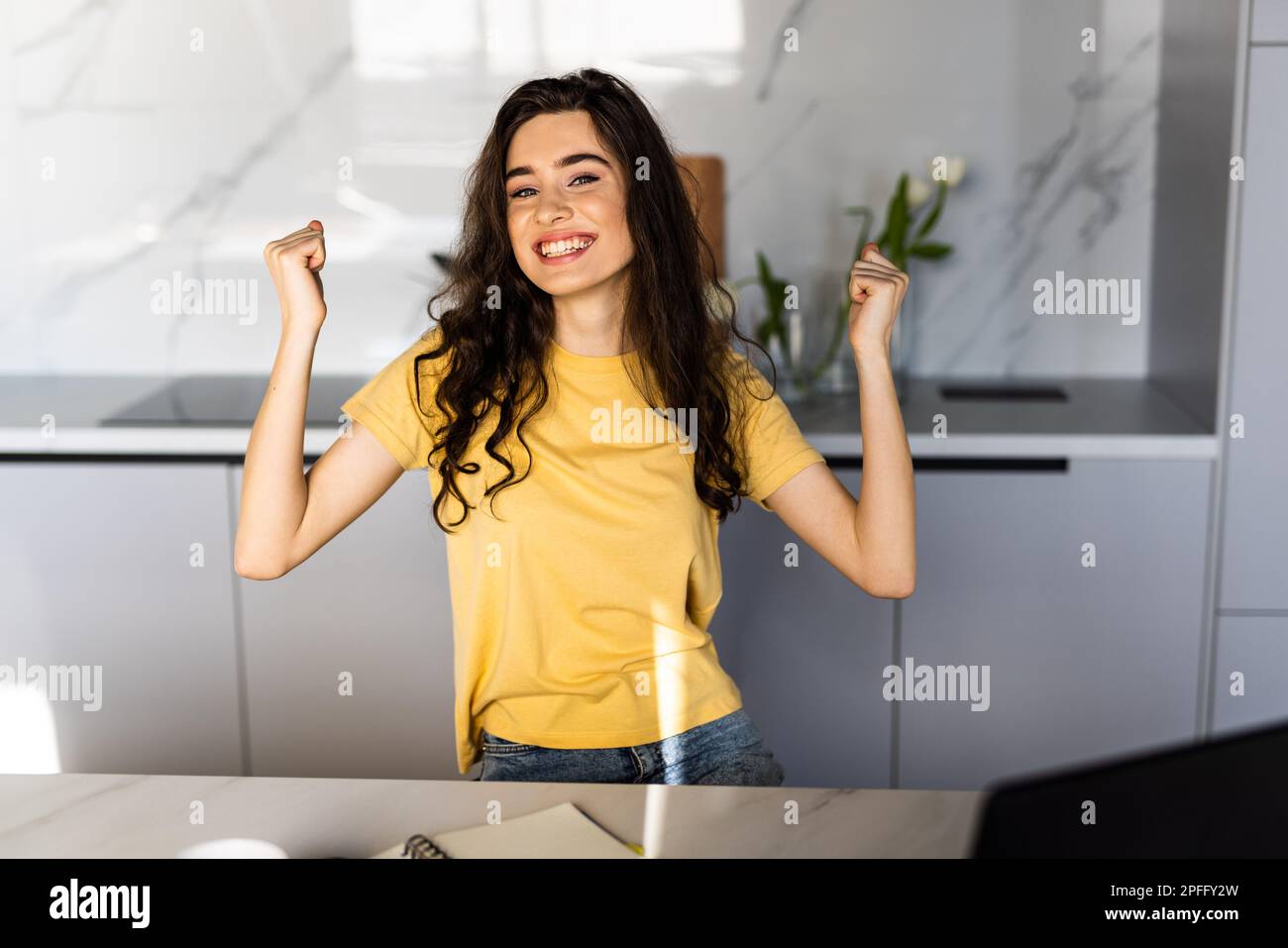Unbelievable. Happy young latina woman sit by laptop at kitchen ...