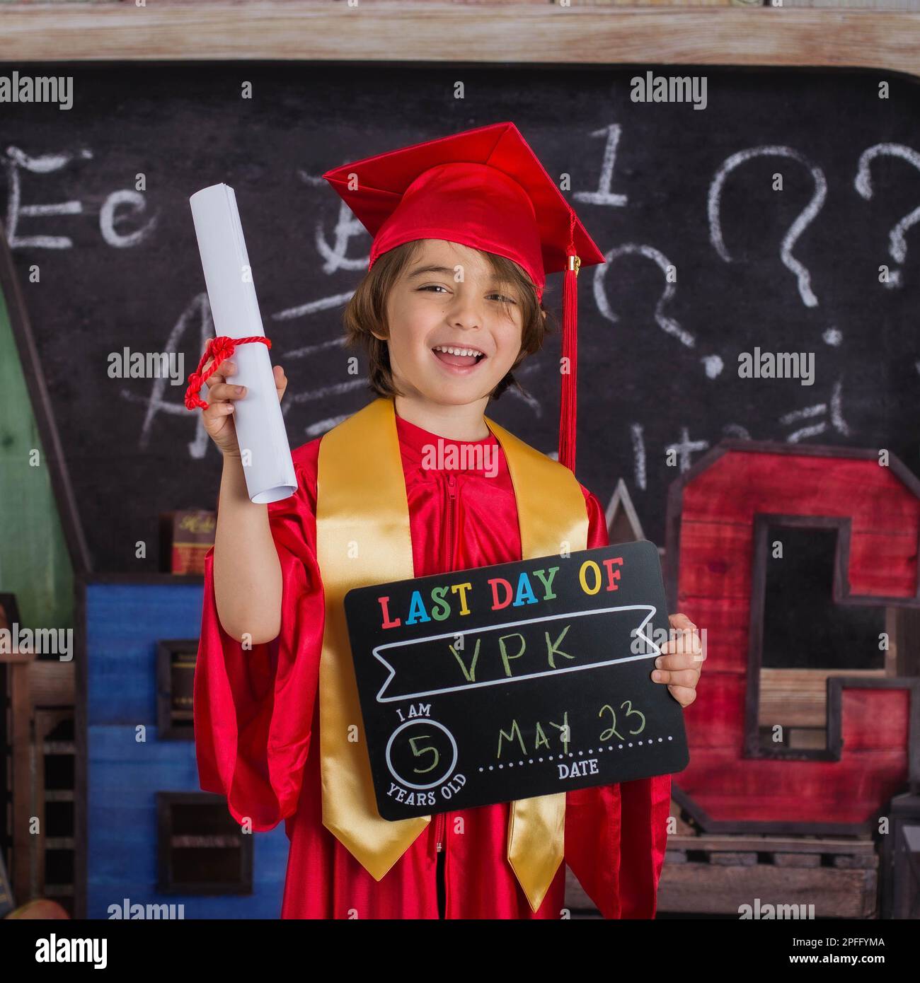 An adorable little boy proudly displaying a VPK diploma during kindergarten graduation program ...