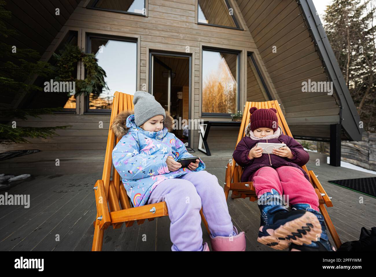 Two little girls sit on chairs at terrace off grid tiny house in the ...