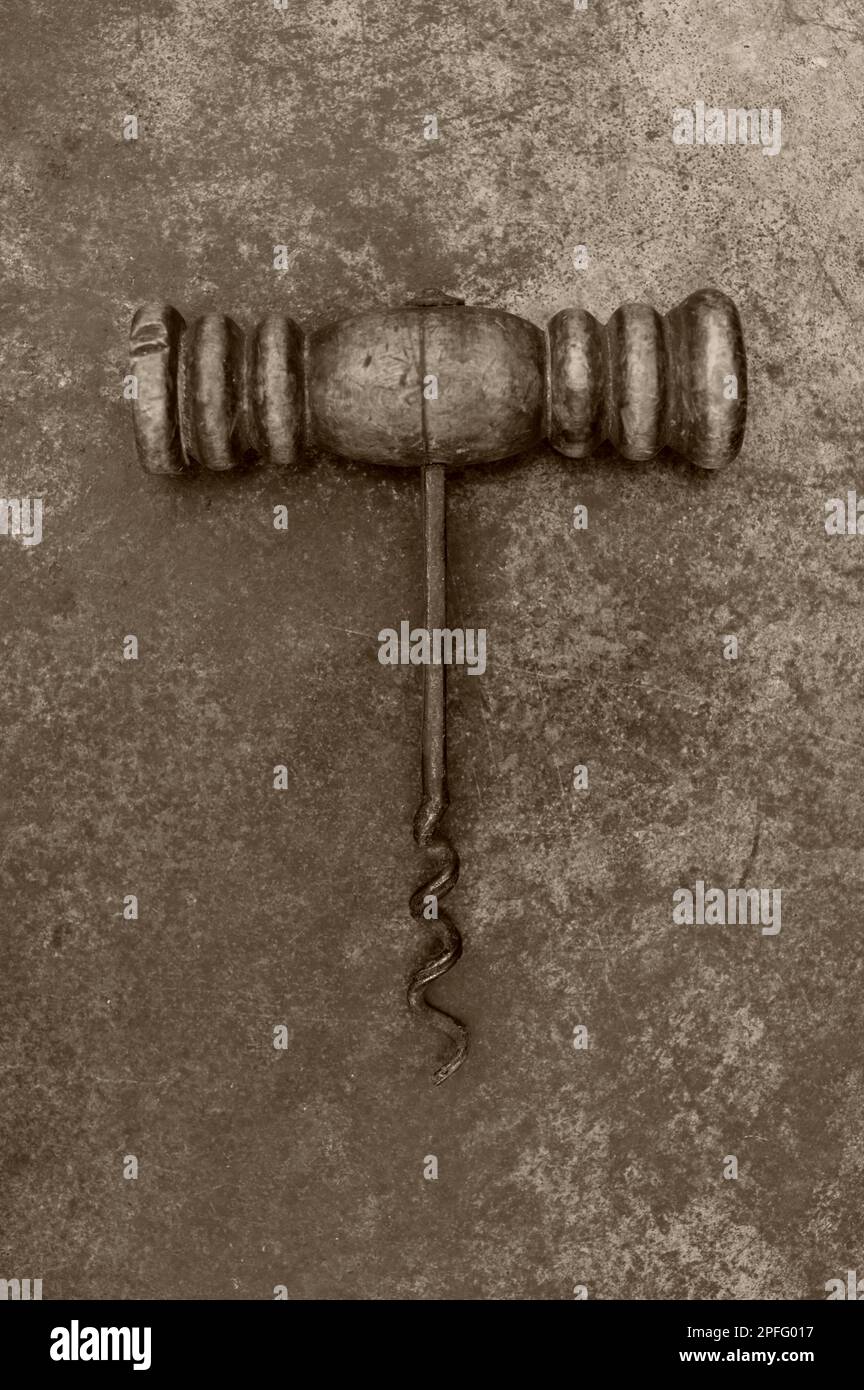 Sepia image of vintage corkscrew with wooden handle lying on tarnished ...